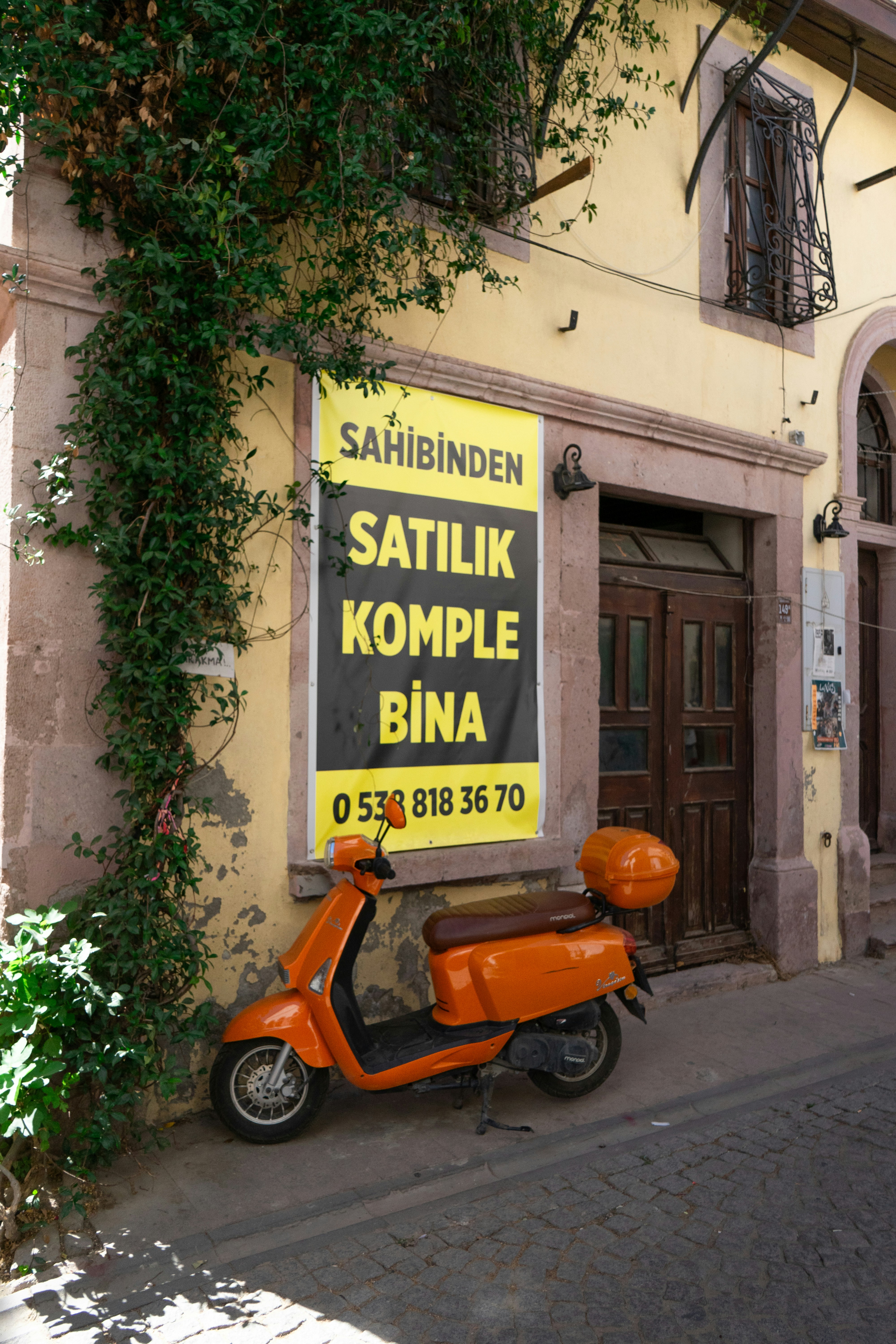 Orange Scooter by the Yellow Sign on a Sunlit European Street