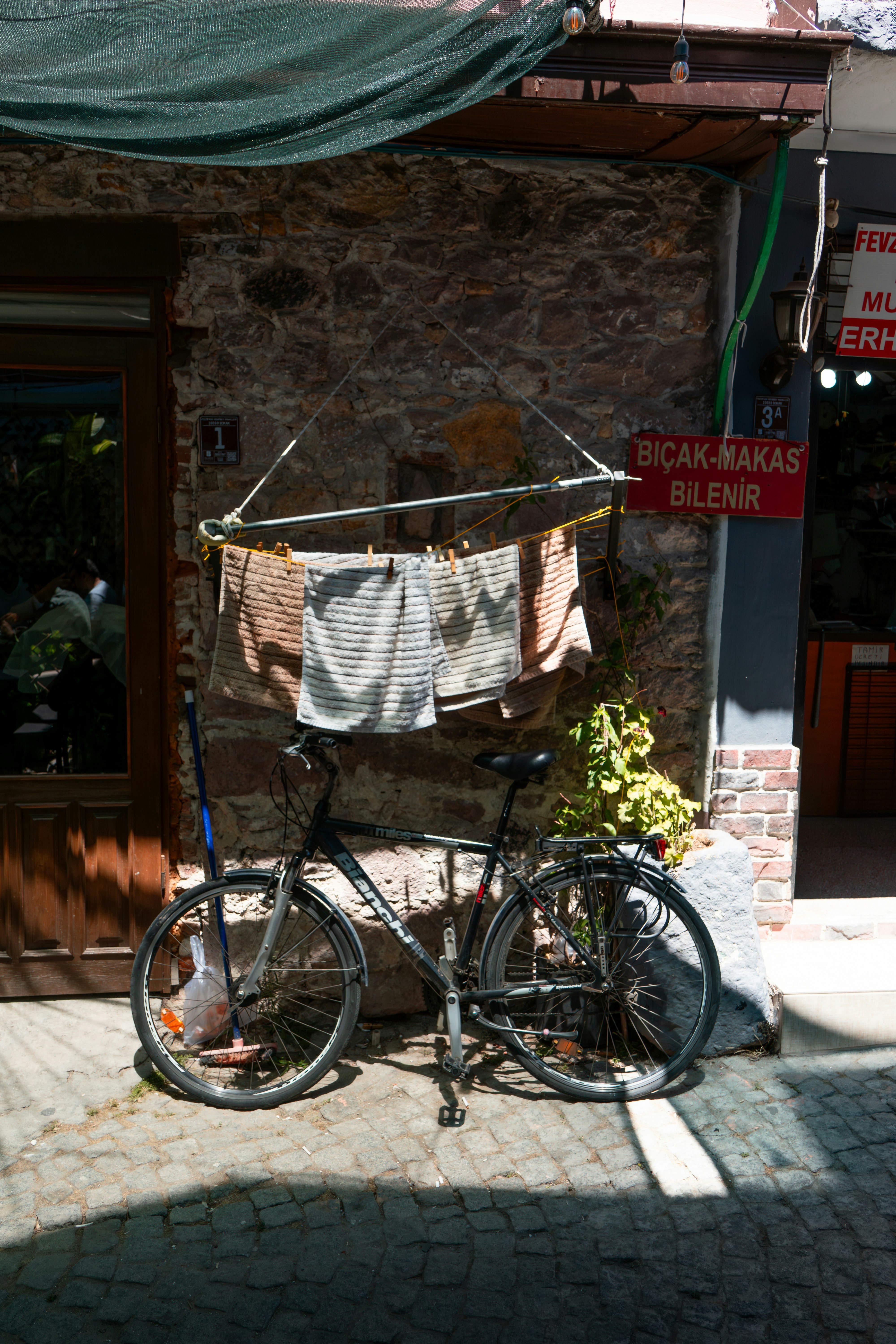 Old bicycle under a drying rack in sunlit alley