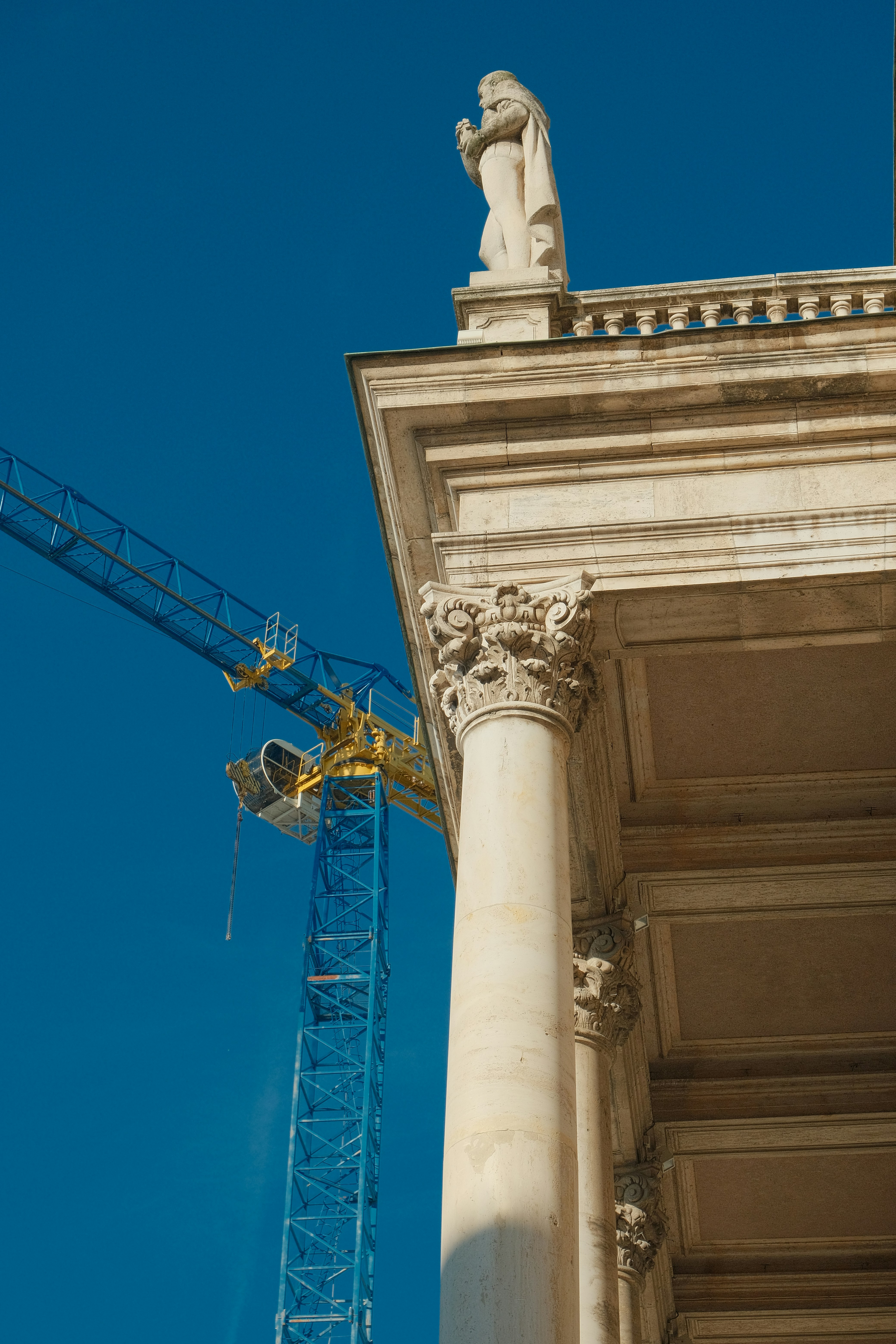 Architectural Crest: Statues and Crane Against a Cerulean Sky