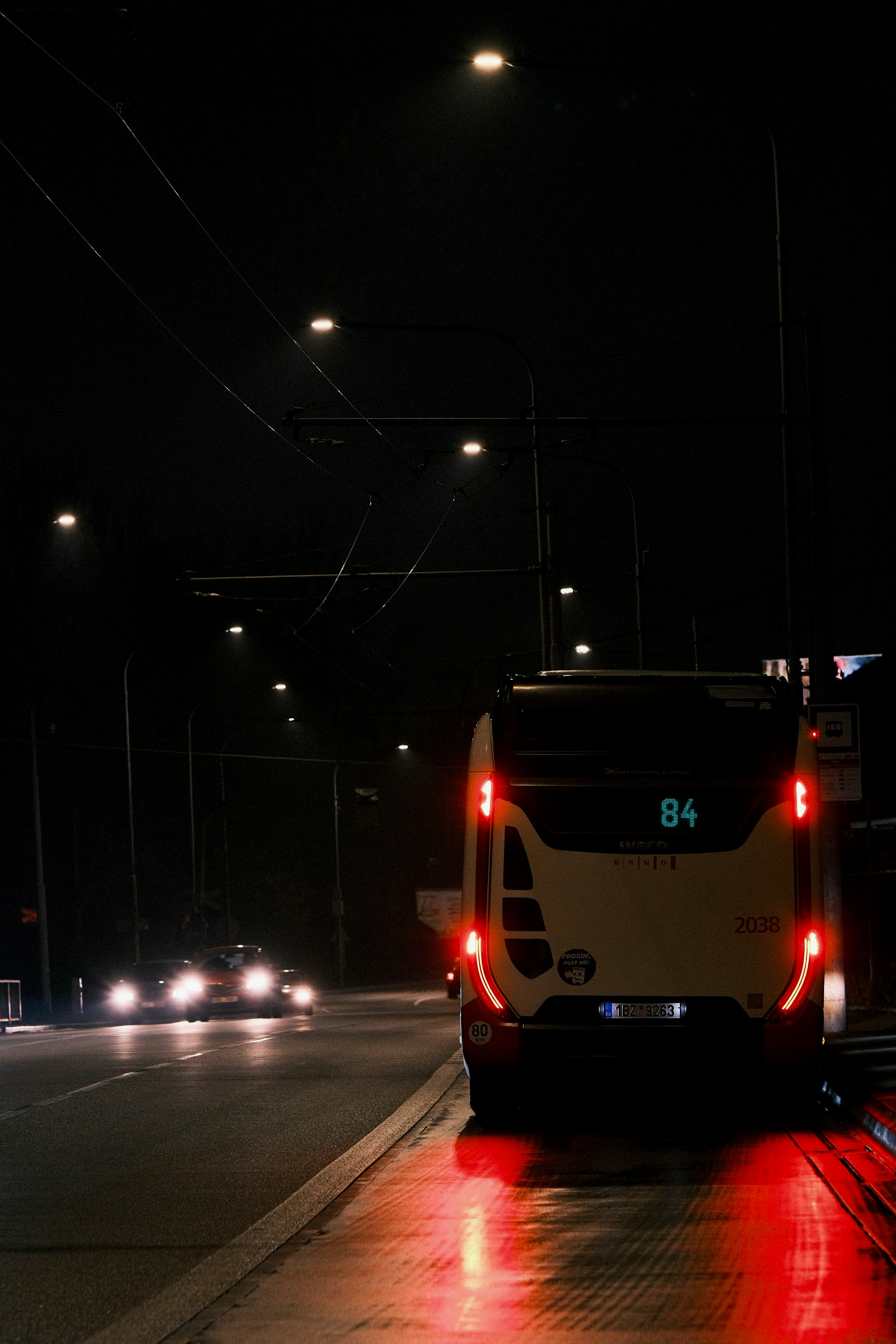 Rear-Glow on a Night Bus Cut Through Velvet Darkness