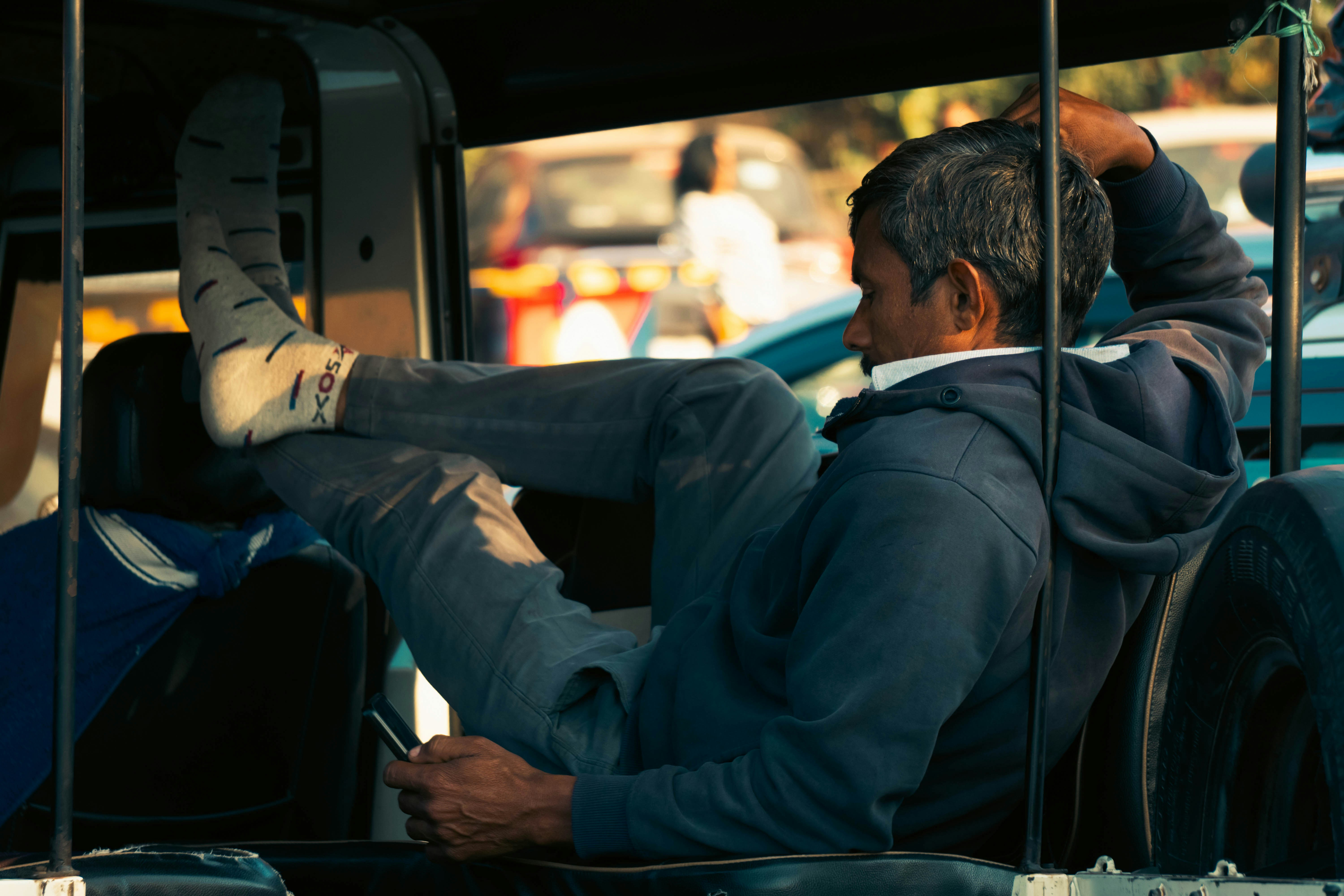 Left-leaning Break: A man resting his feet inside a cluttered vehicle