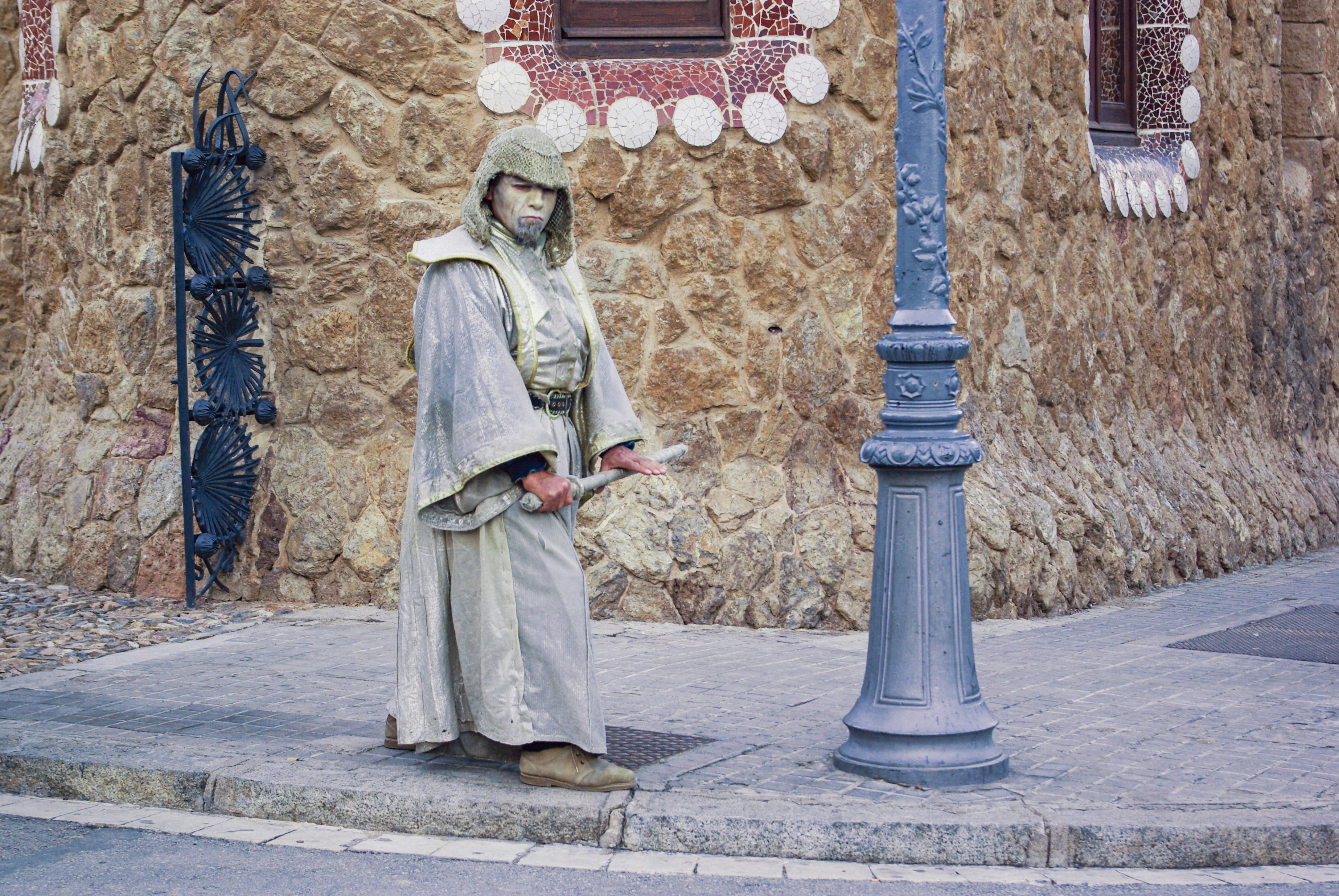 Man in costume stands by lamppost near stone building