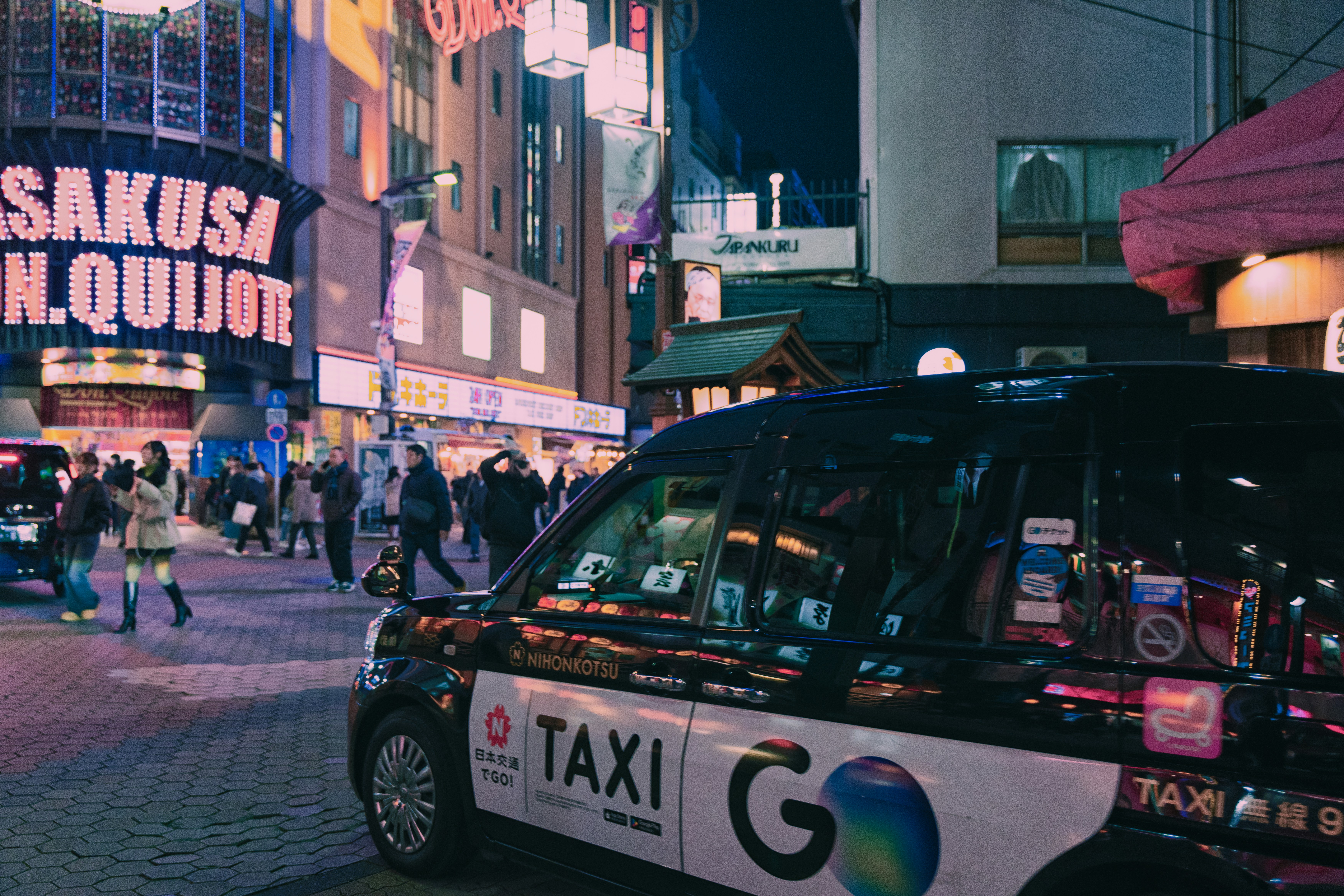 Night bustle and a taxi: neon glow over a crowded city street