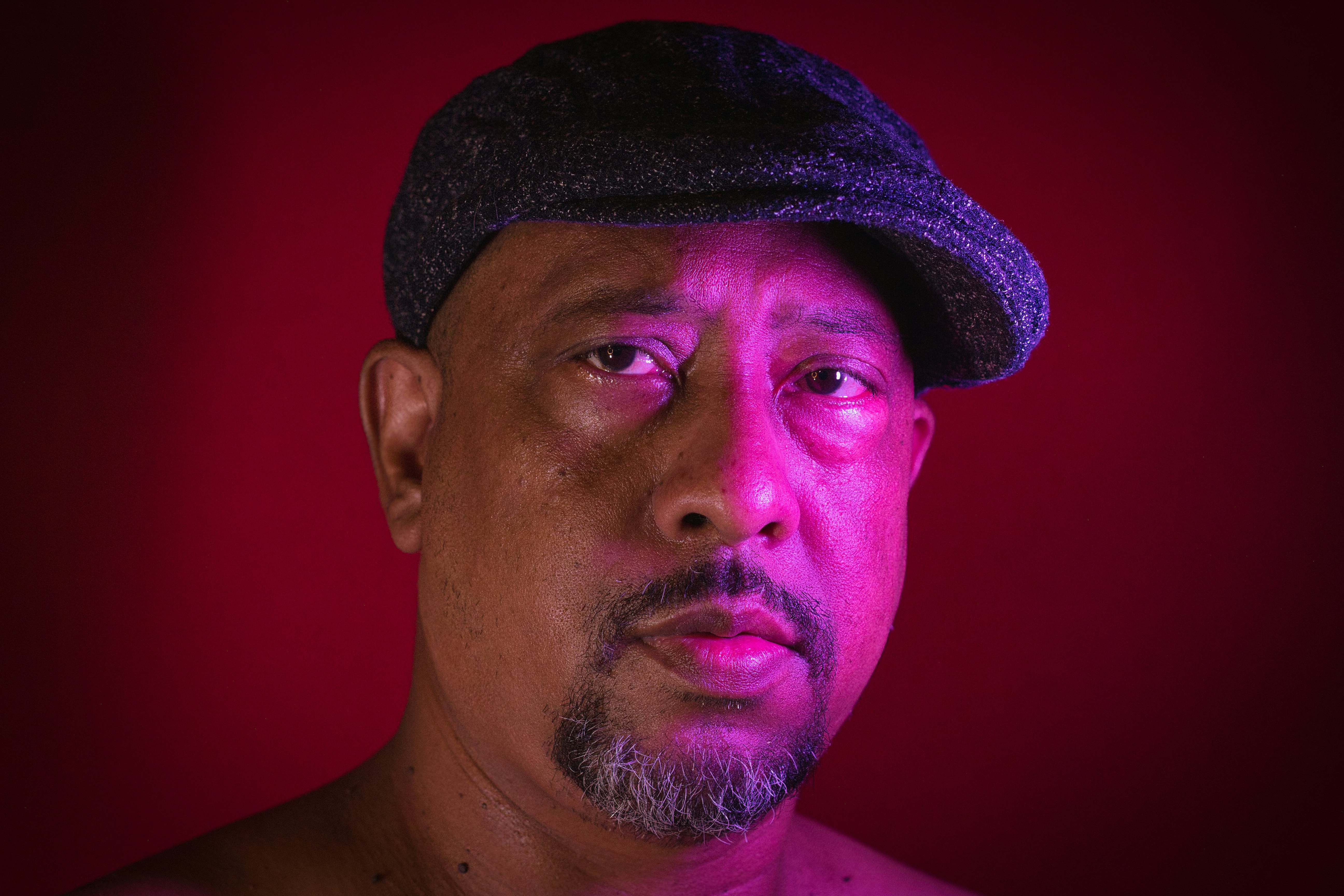 Neon-lit Portrait: A Calm Gaze Beneath a Flat Cap
