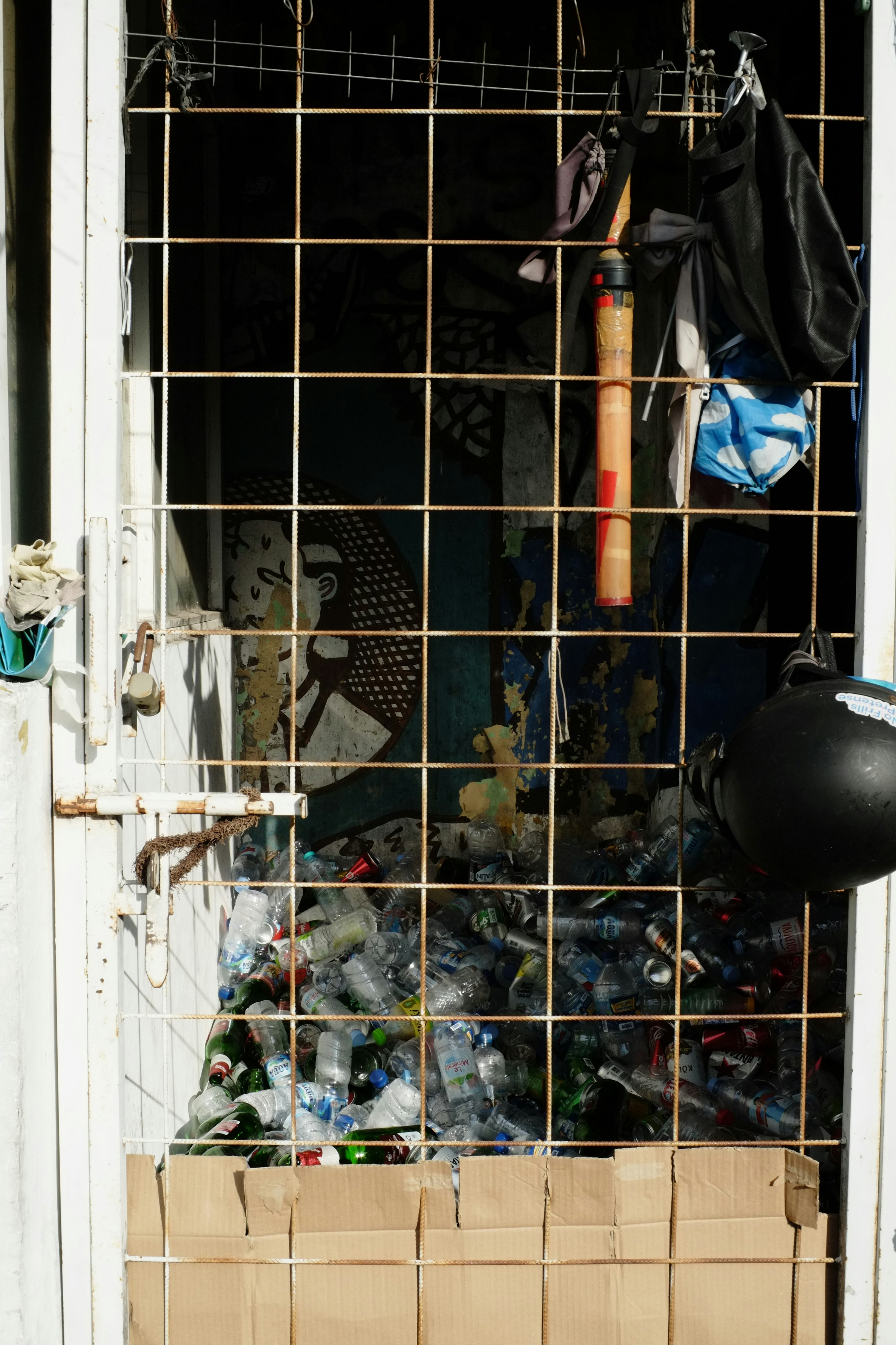 Prison Gate of Litter: A cluttered doorway behind a rusted lattice