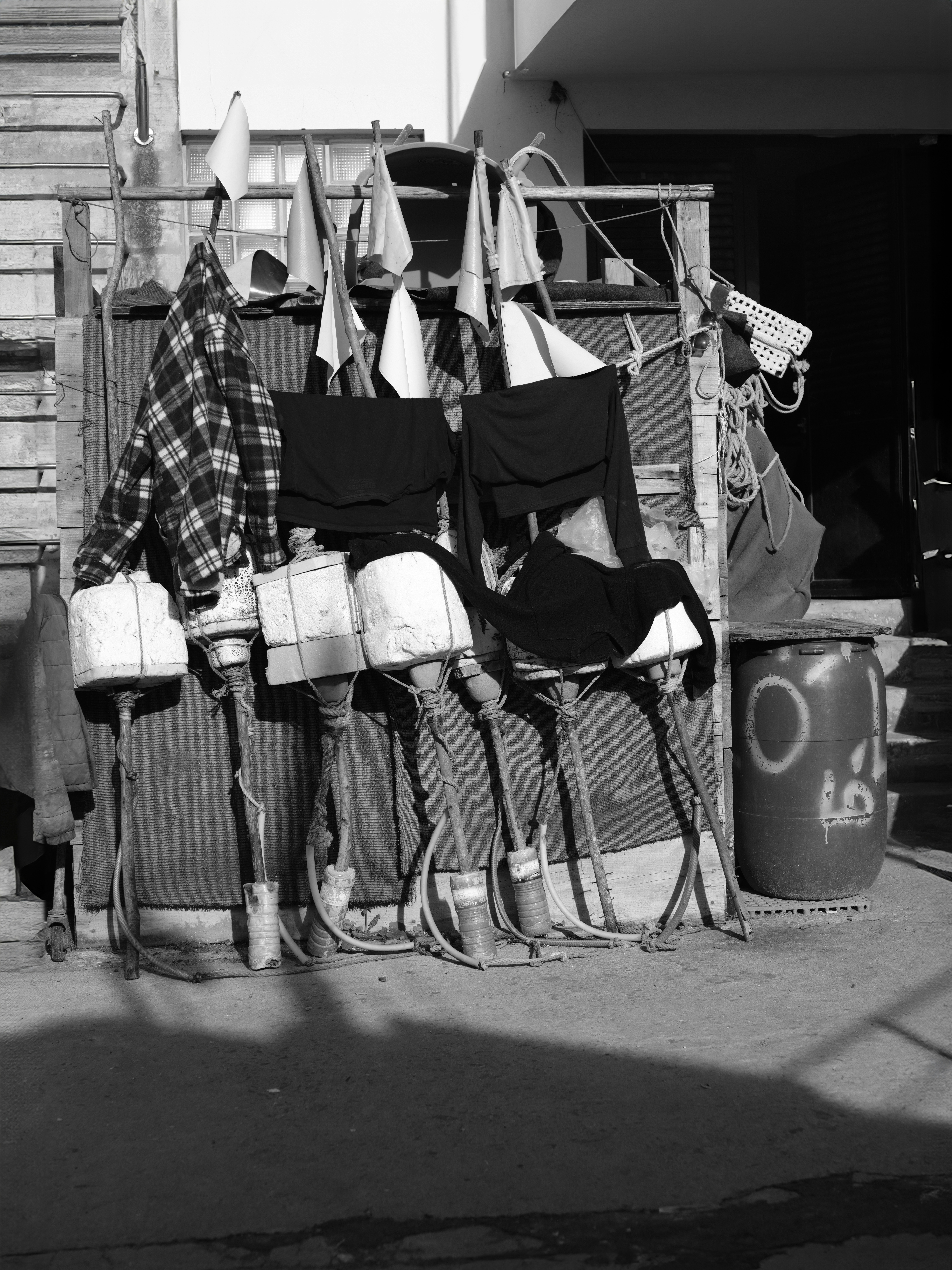 Row of worn-out boots and gear drying behind a workshop fence as daylight fades