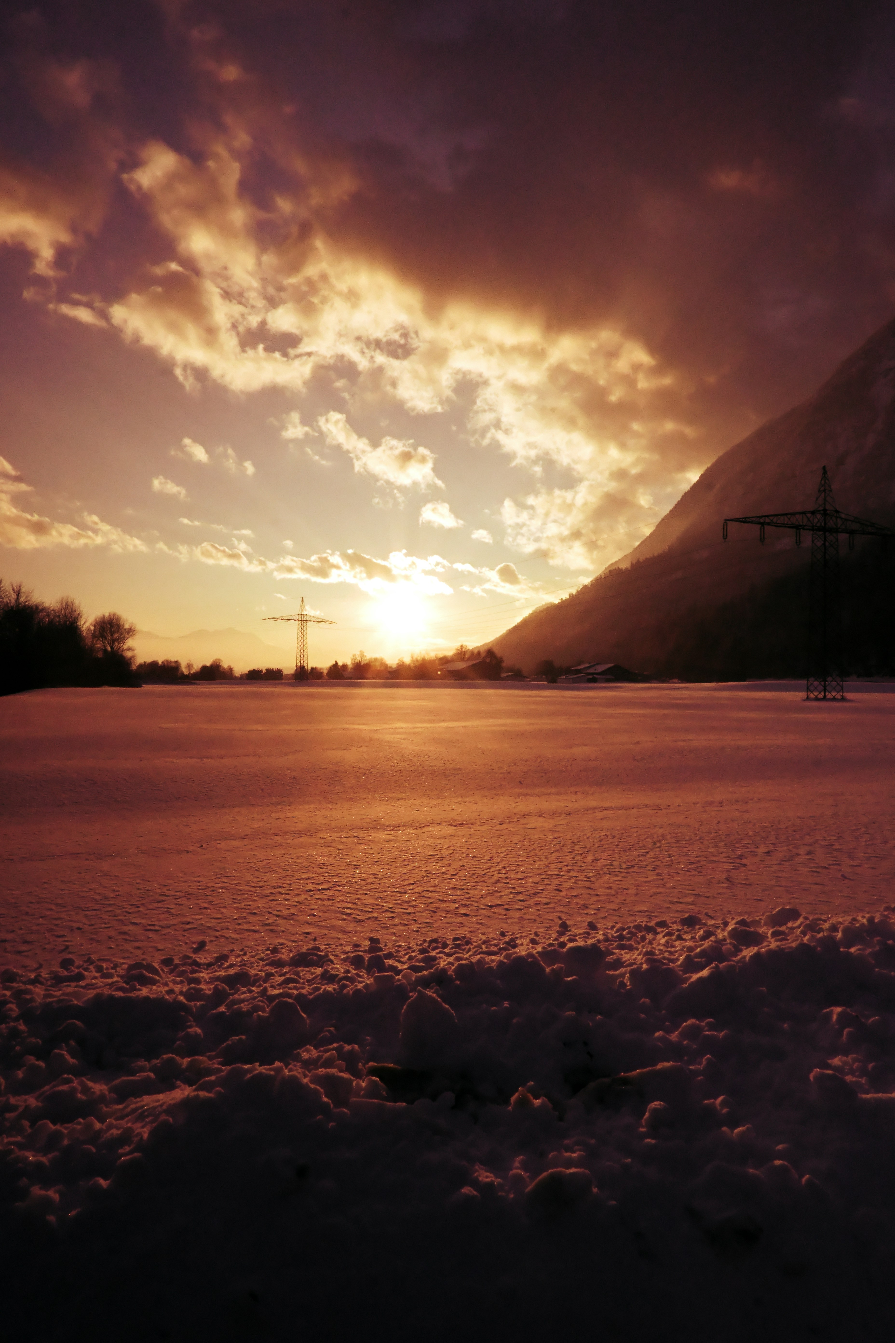 Sunlit Horizon Over Snow: A Quiet Dusk Beneath a Distant Peak