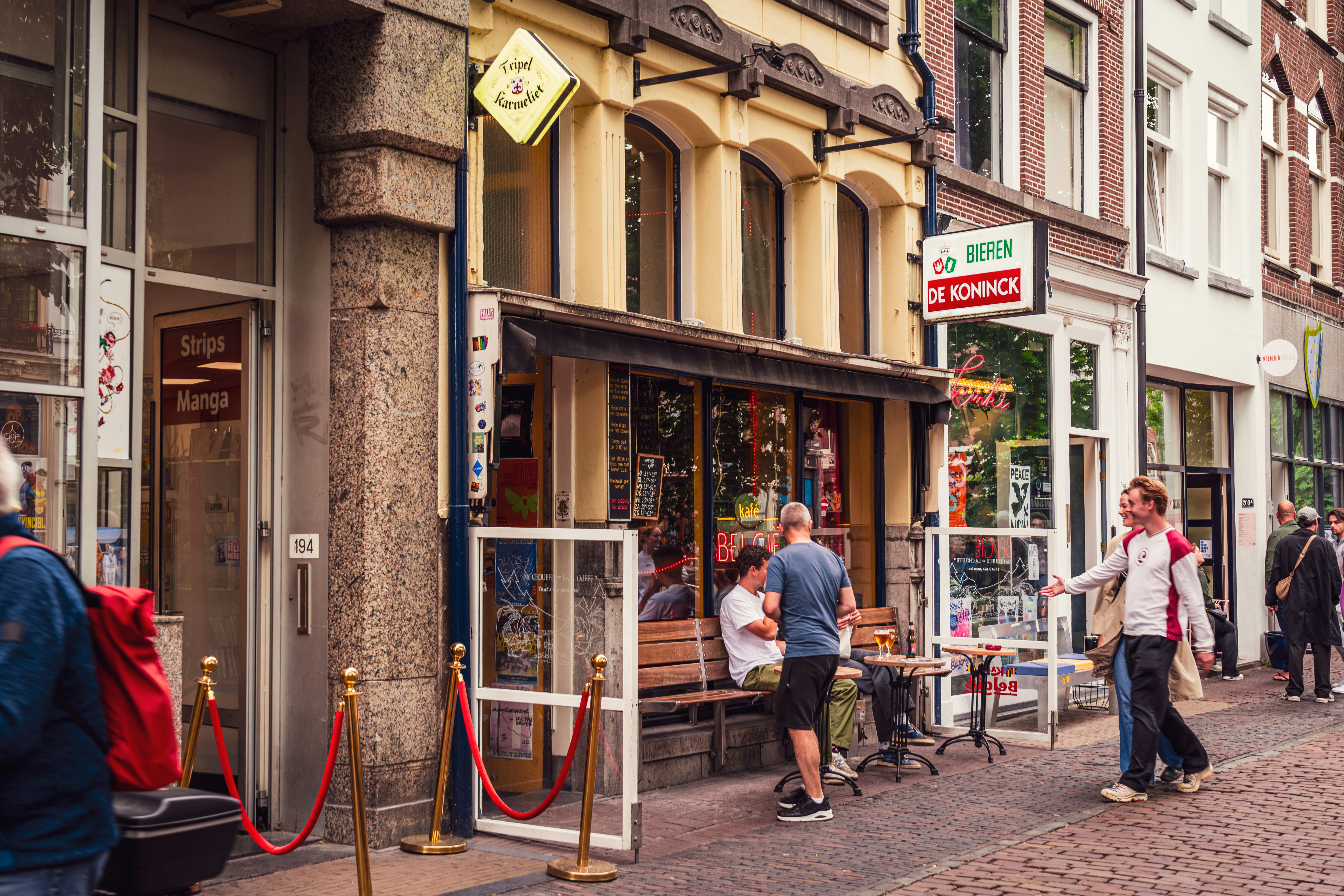 Exterior of Café De Koninck, a Belgian beer bar in Utrecht, Netherlands, featuring beer taps, vintage brewery signs, and a lively street atmosphere.