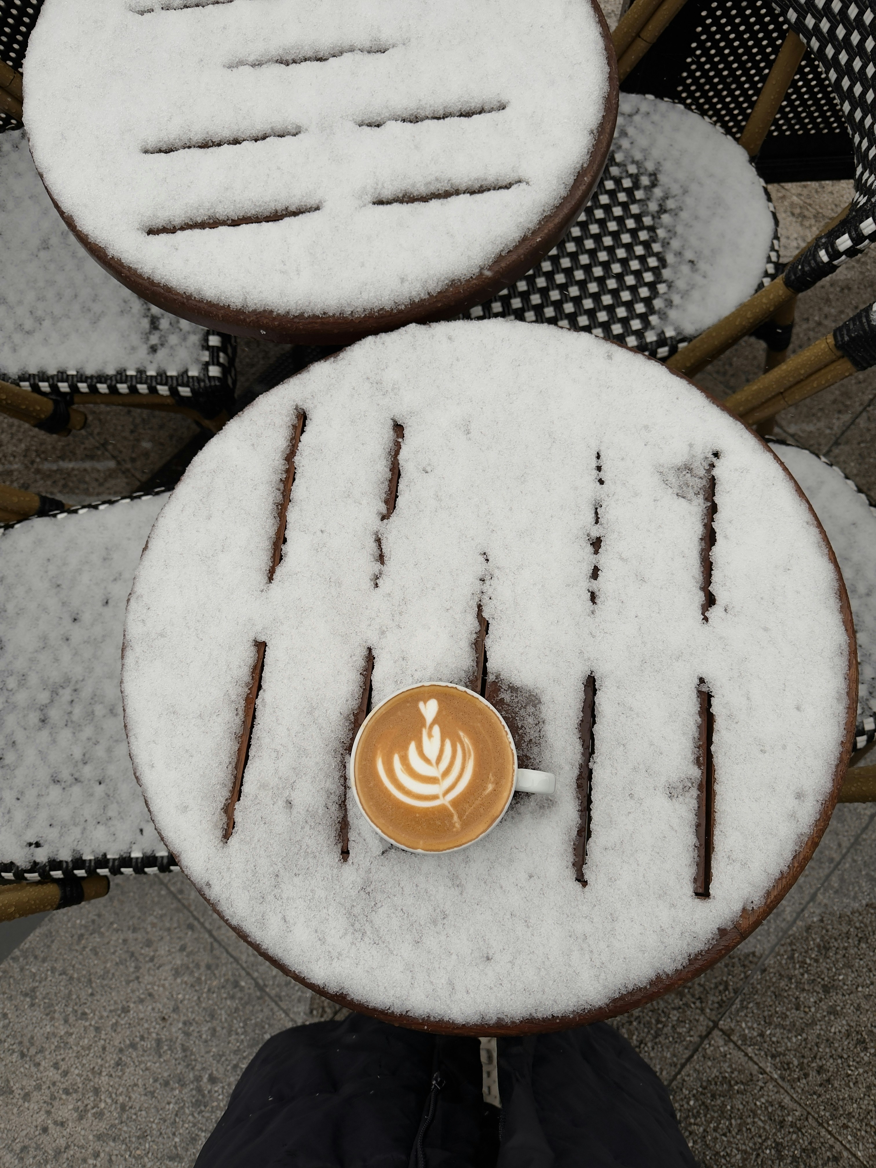Coffee with latte art on a snow-covered cafe table