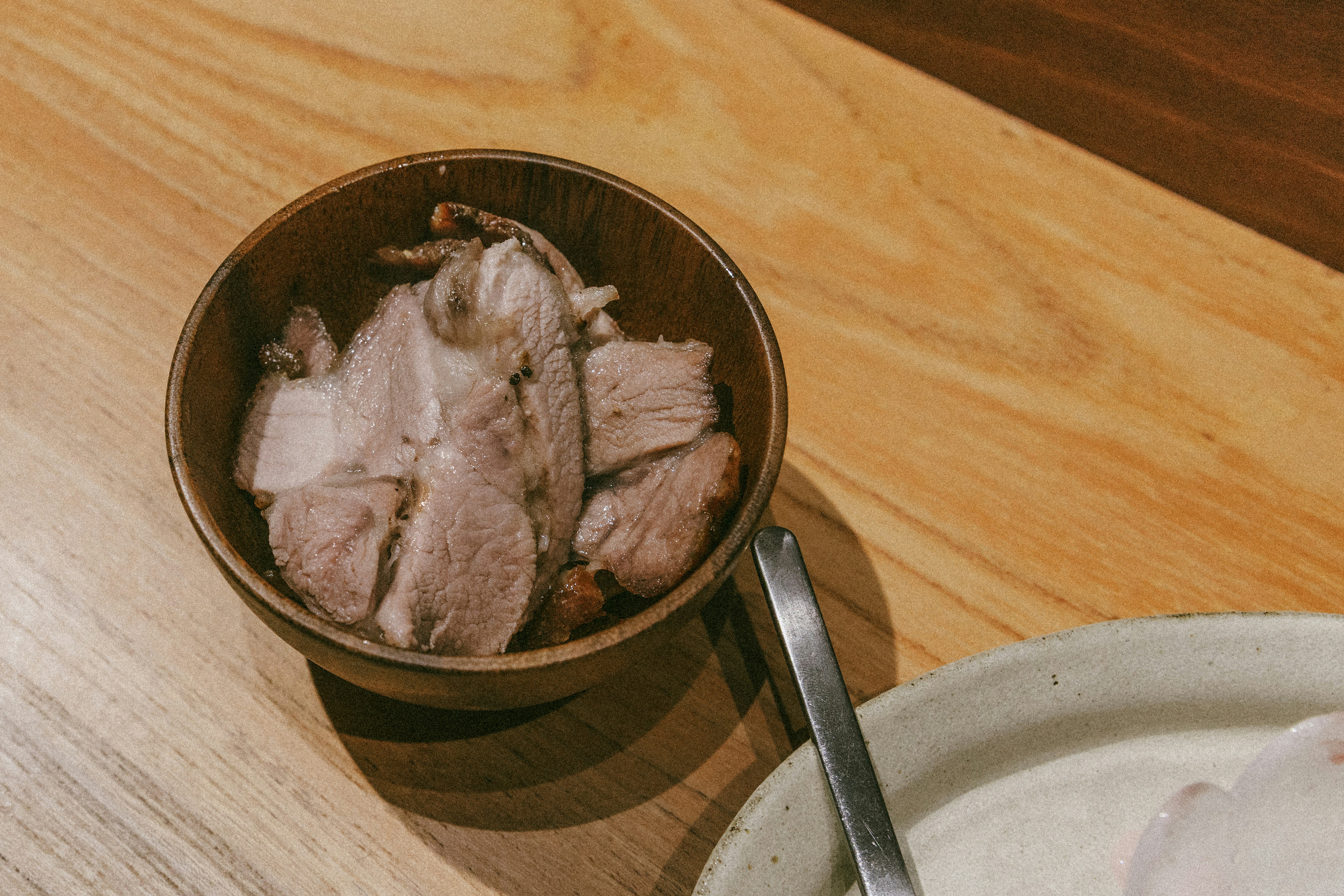 Bowl of Sliced Meat on Wooden Table