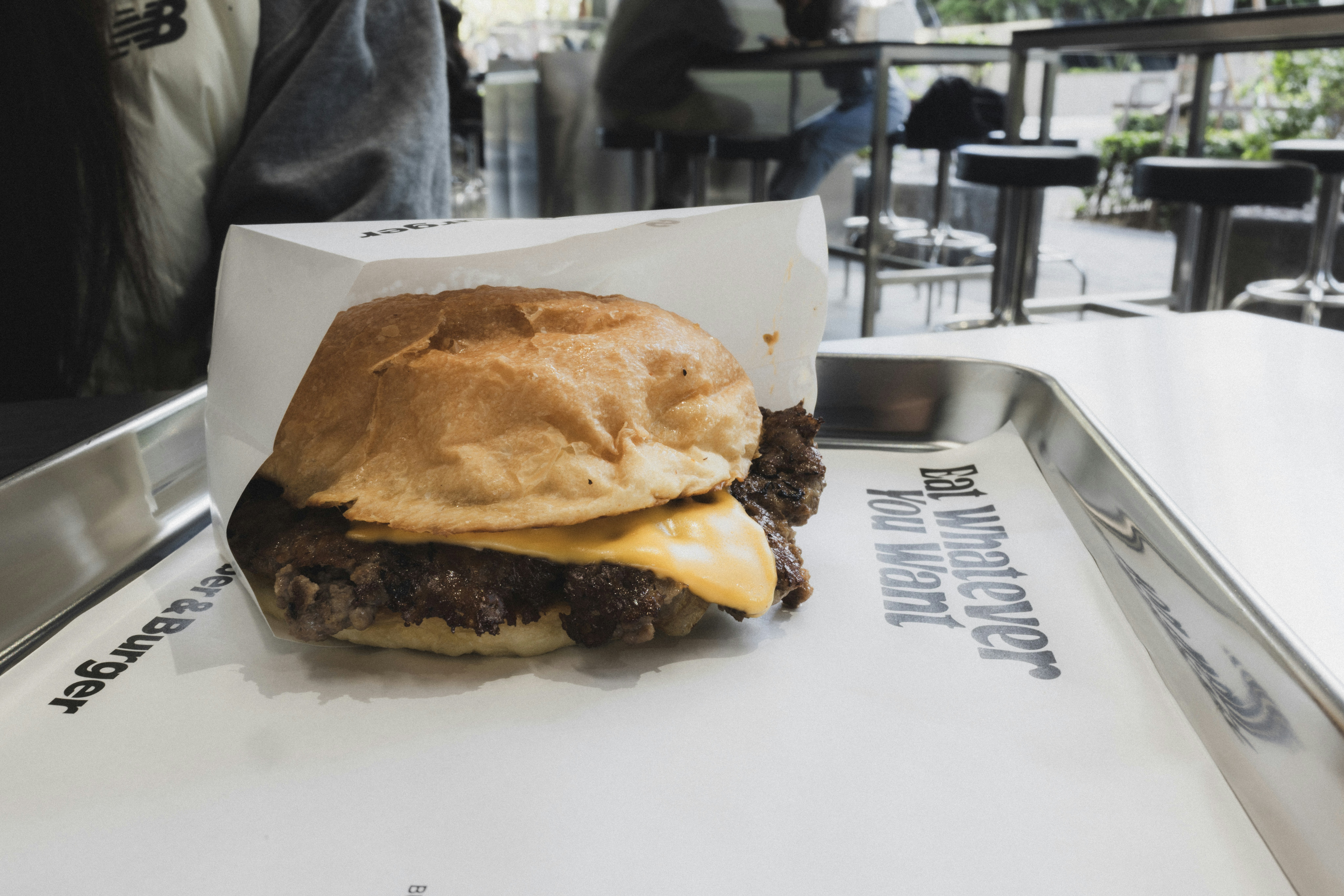Midday Bite: A Cheeseburger Nestled on a Tray at a Bright Café