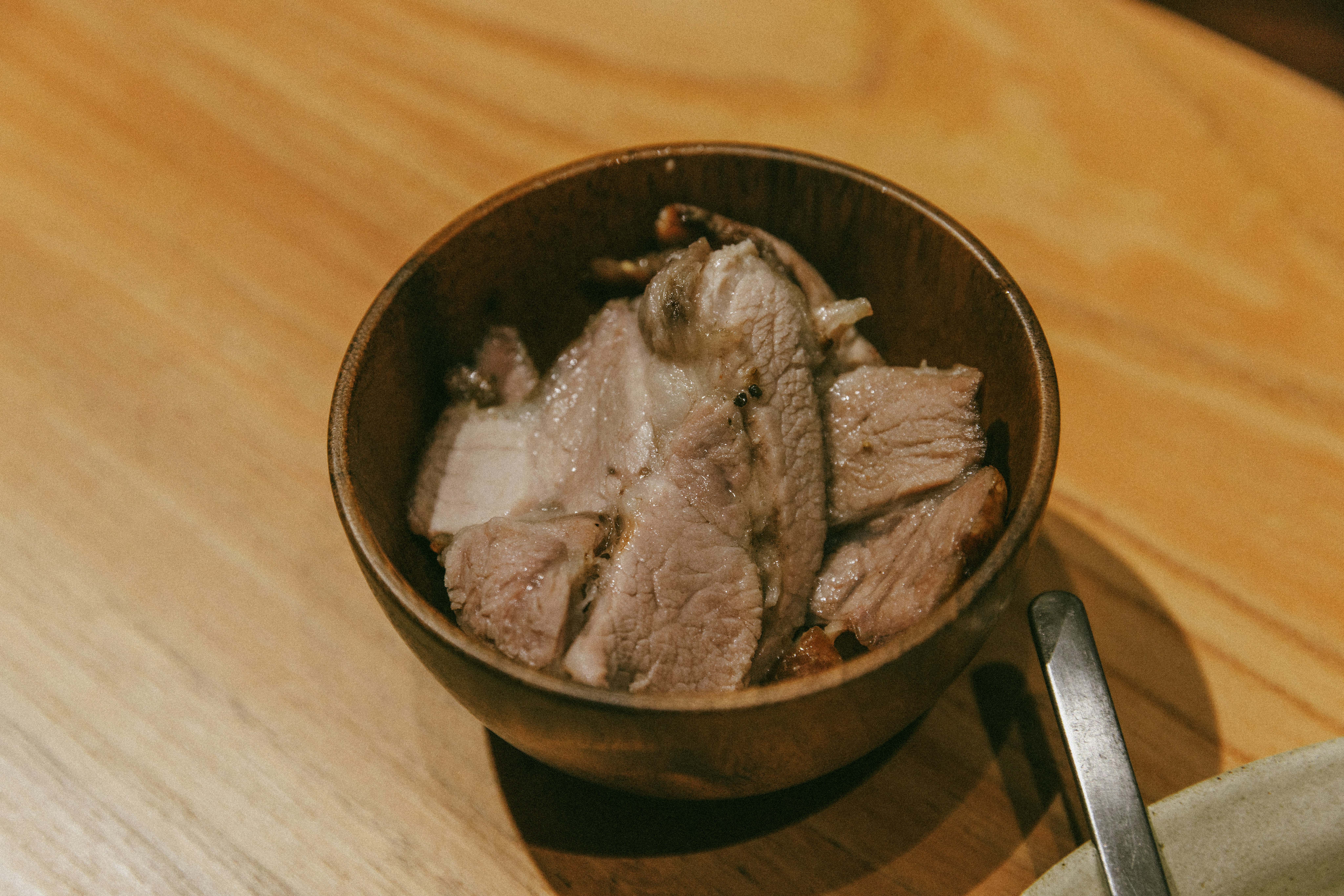Sliced pork over a warm wooden bowl