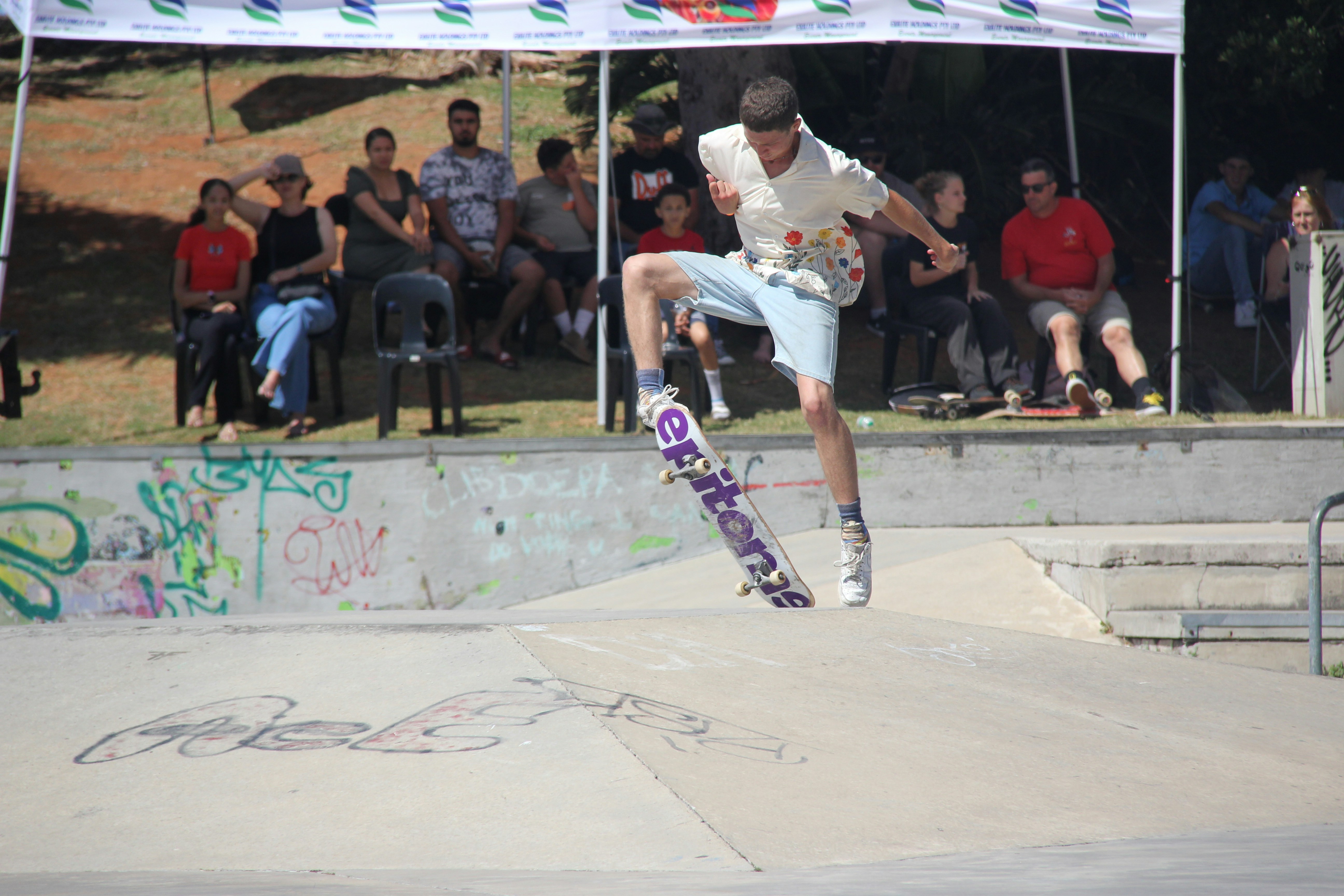 Skateboarder in mid-air over a graffiti-streaked skatepark bowl