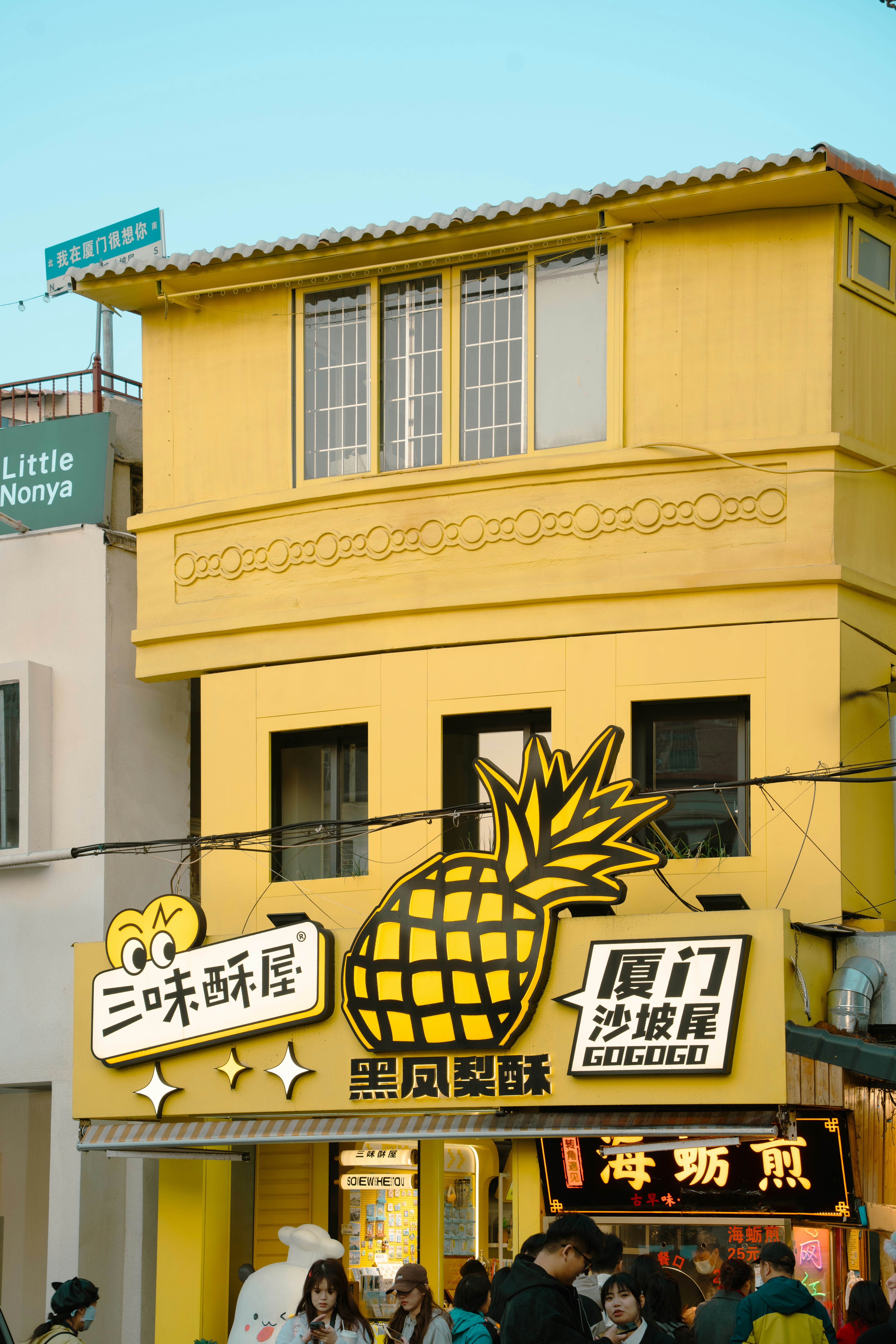 Bright Yellow Corner: A Pineapple Sign Above a Bustling Street Eatery