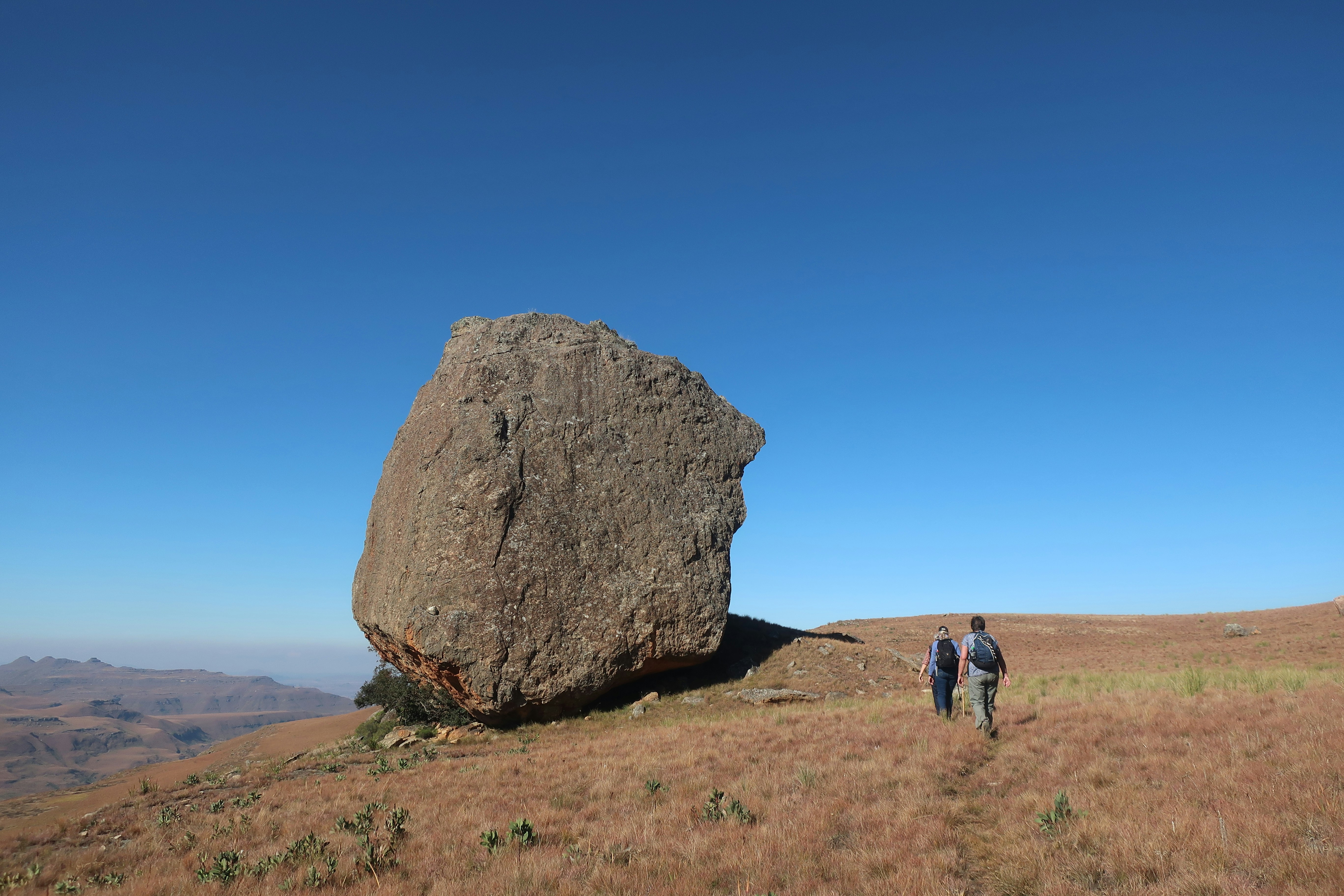 Stone Sentinel: A Bold Boulder and Two Hikers Against the Open Sky