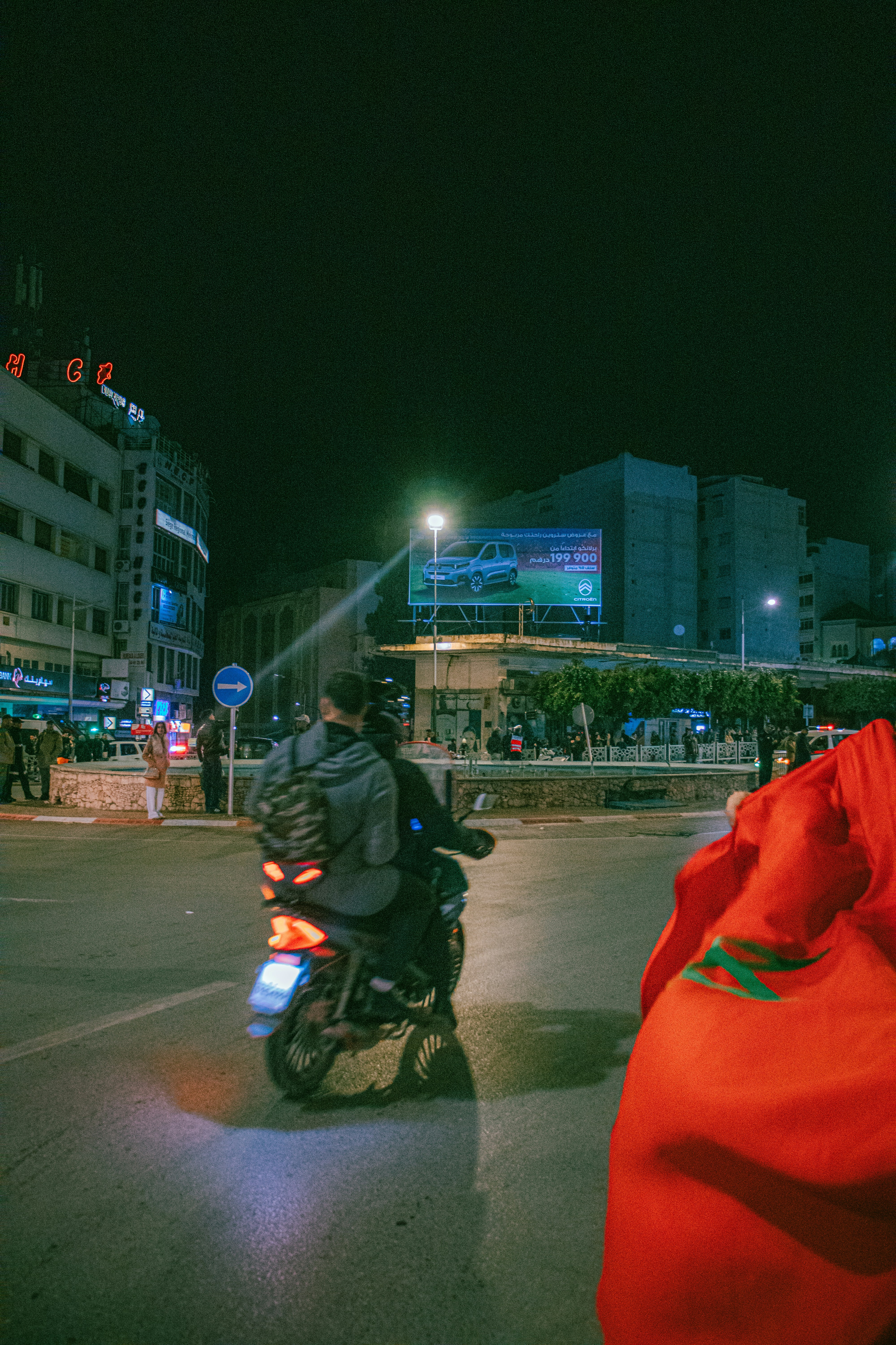 Midnight Street Ride: Headlights, Red Garment, and City Lights