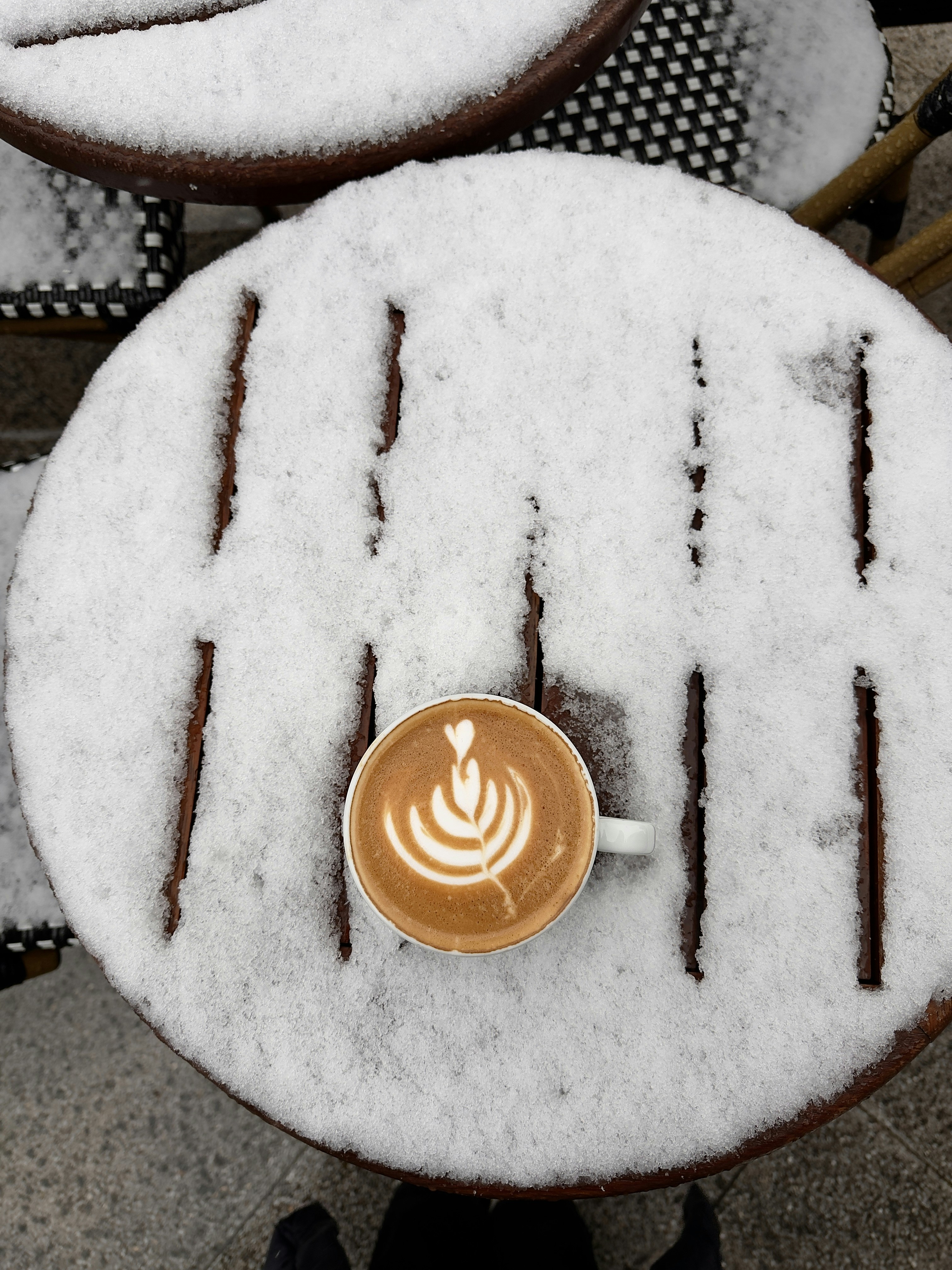 Coffee with latte art on a snow-covered table