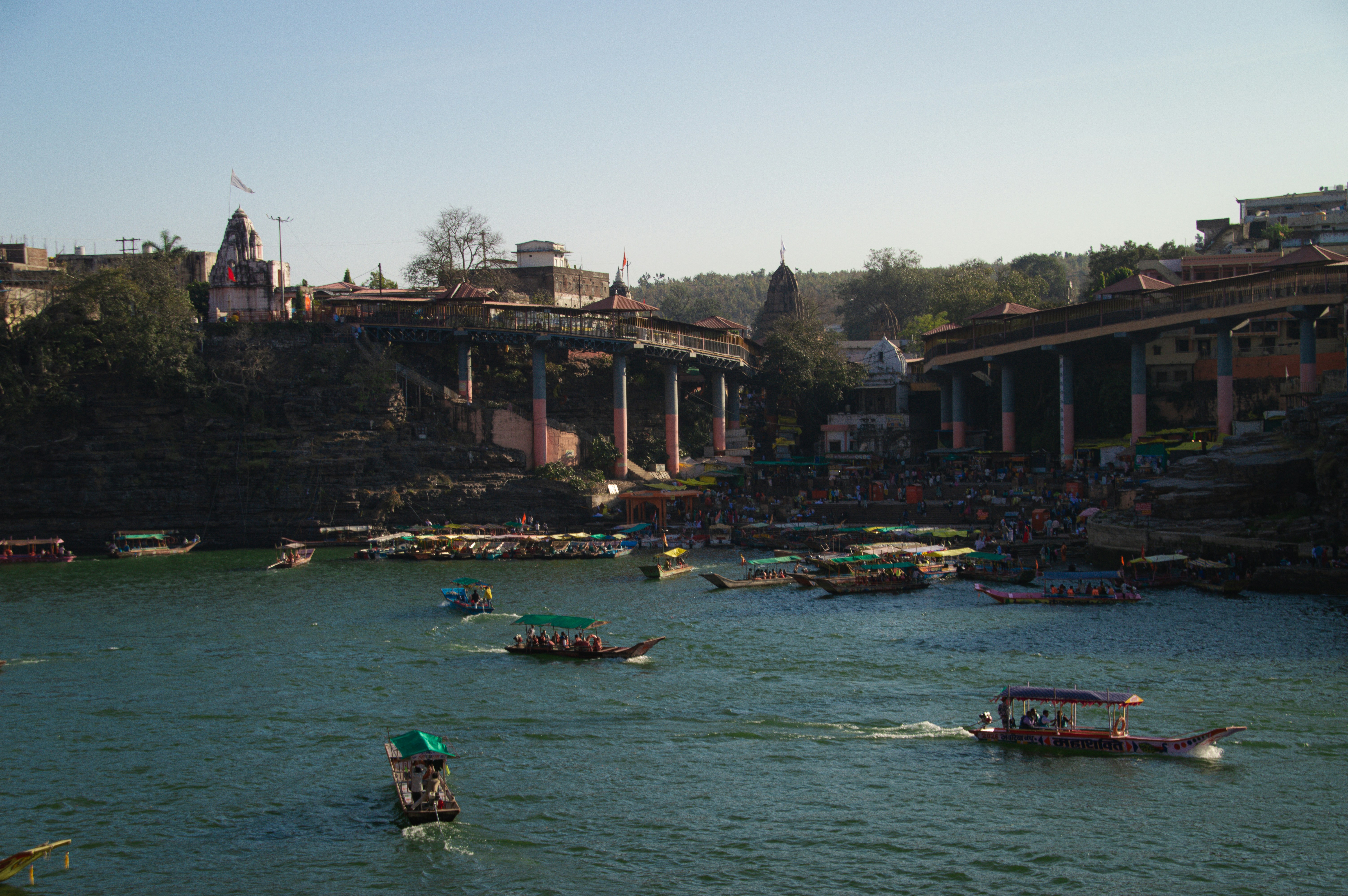 Riverside Bridgefront: Boats drift under a sunlit riverbank