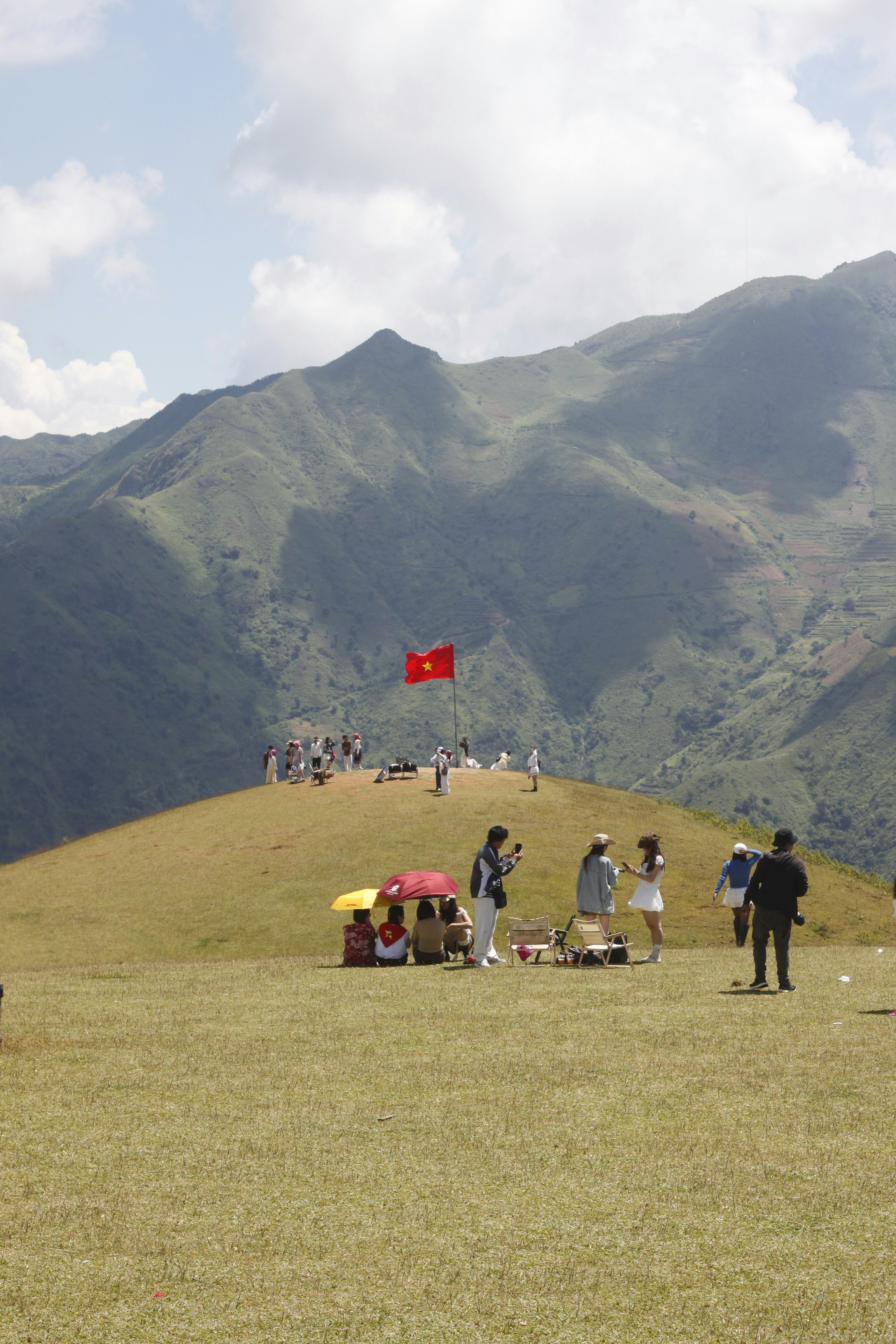 Red Flag atop the Hill: People Gather at a Scenic Mountain Vista