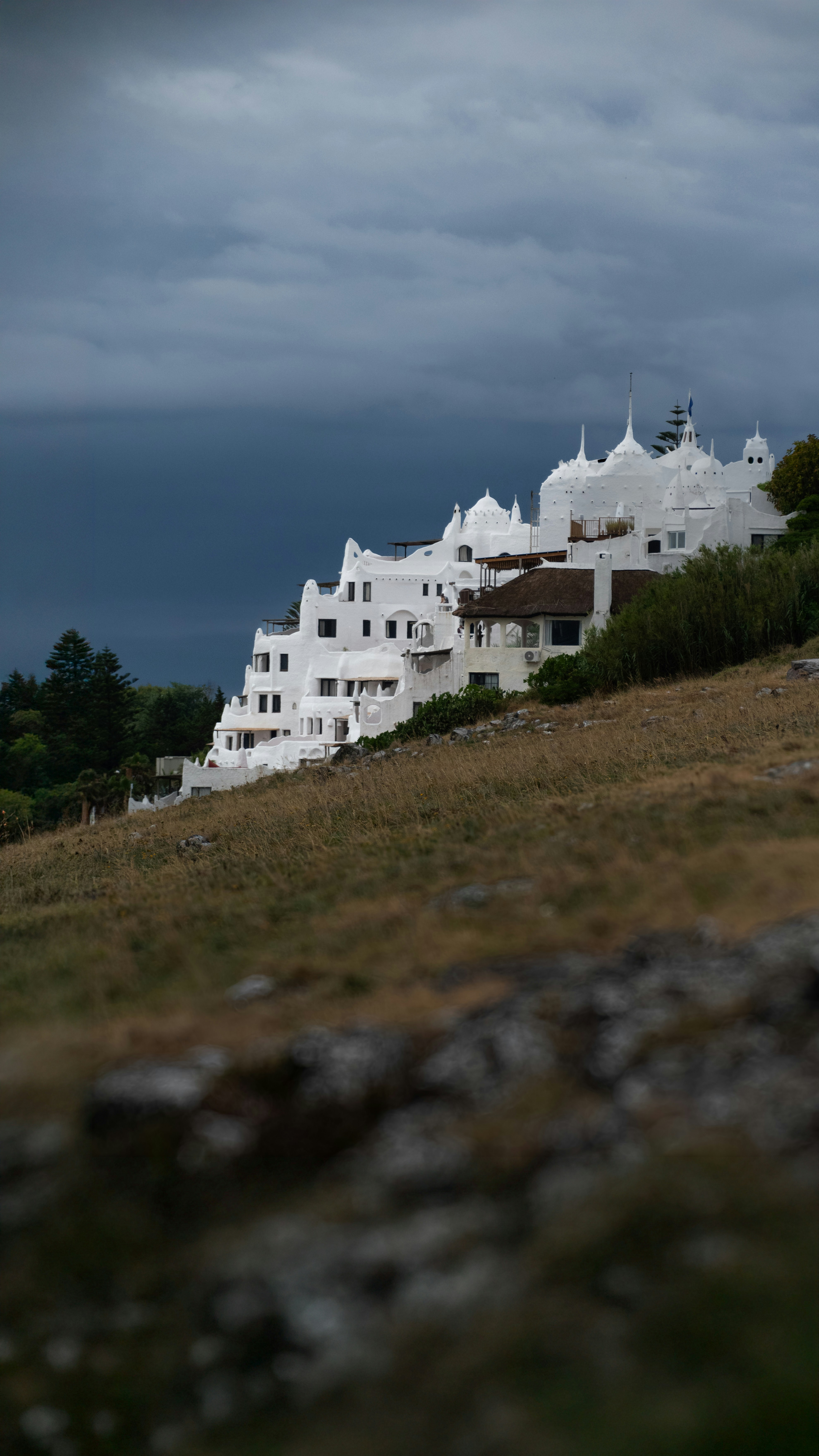 White-washed villa cluster clinging to a hillside under a stormy sky