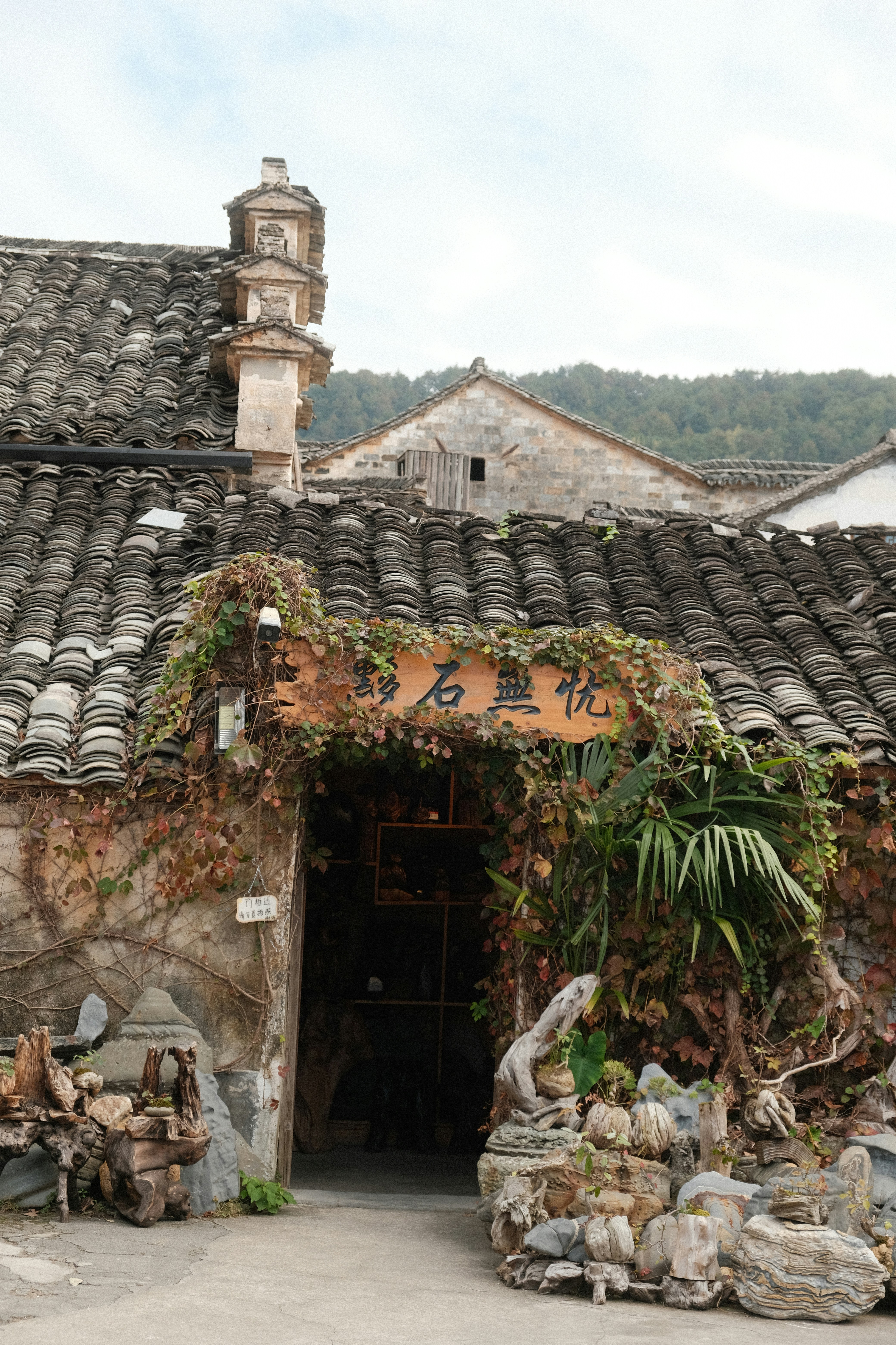 Stone Lanterns and Vines Guard a Weathered Entrance into a Village Workshop
