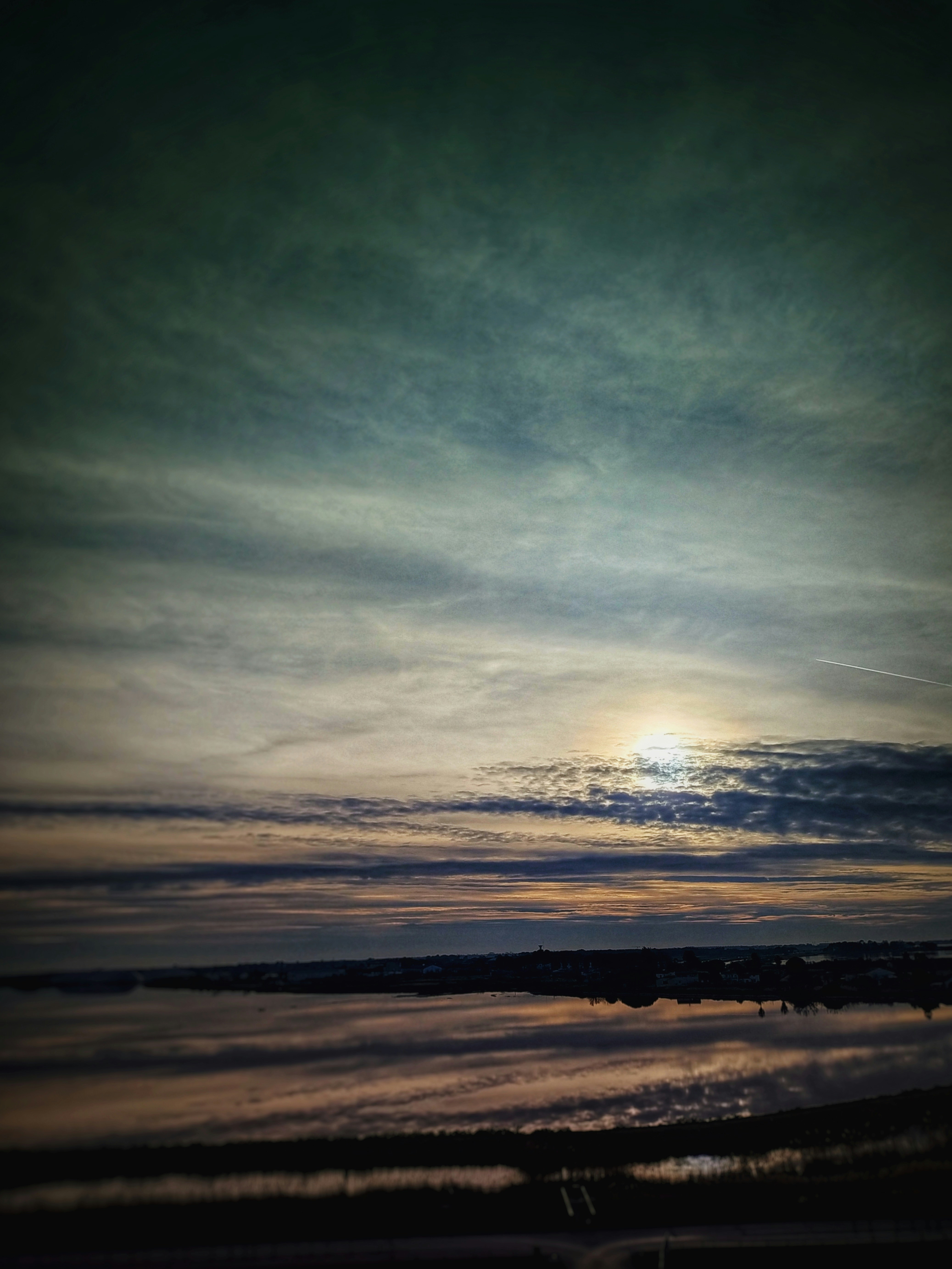 Sunset over a calm body of water with clouds.