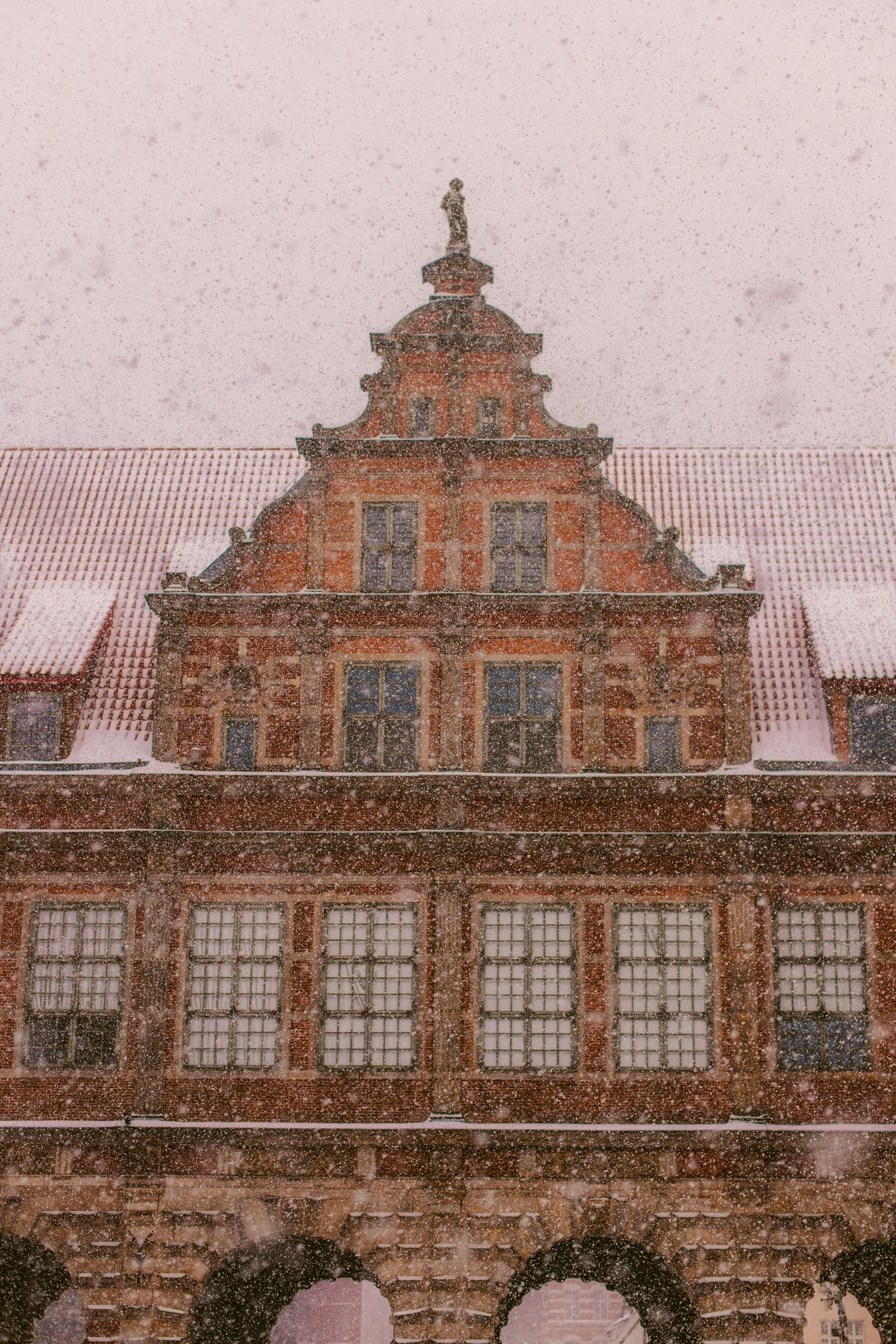 Winter Facade in Snowfall: A Historic Gable in Soft Light