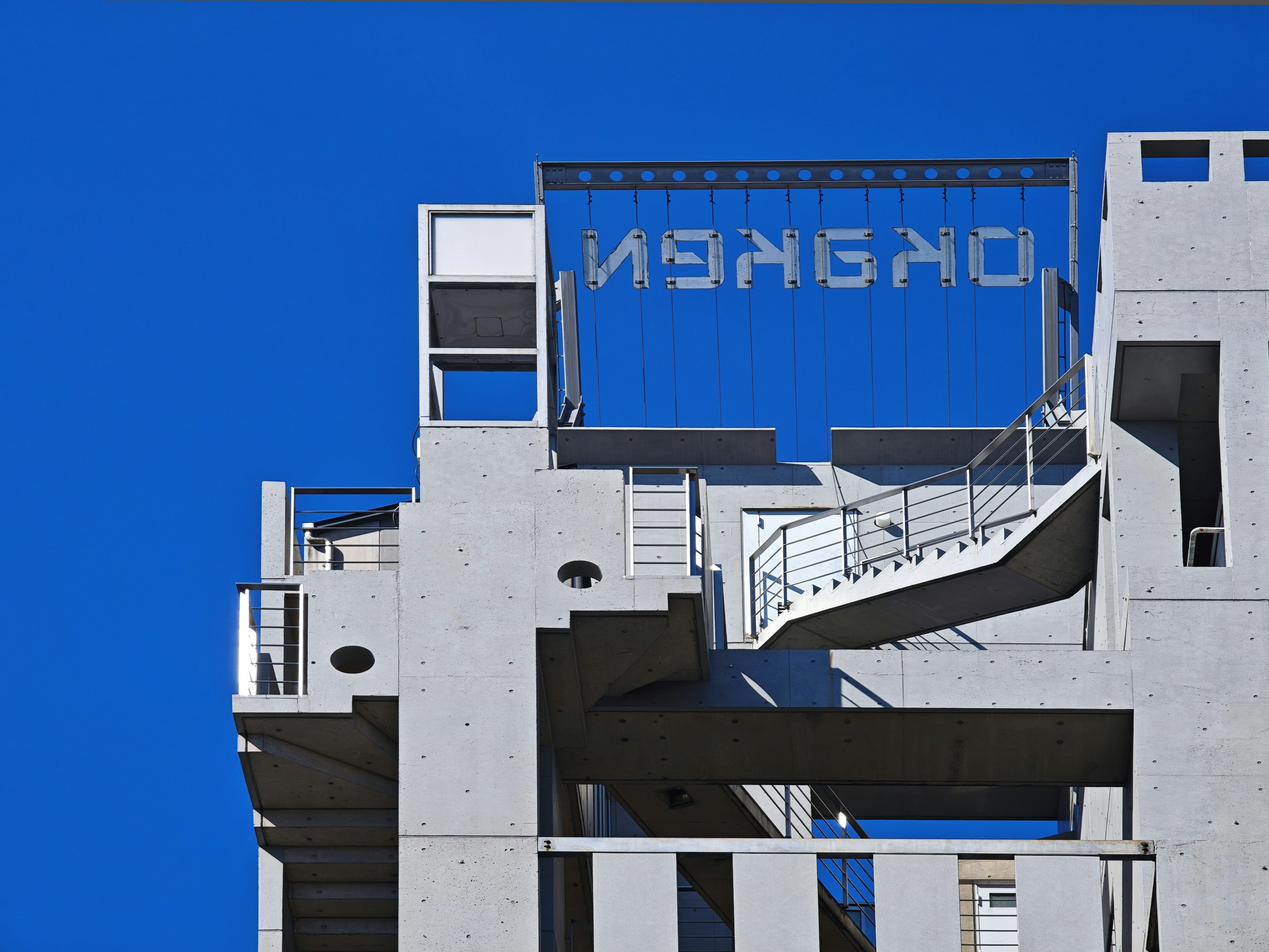 Modern concrete building with stairs against blue sky