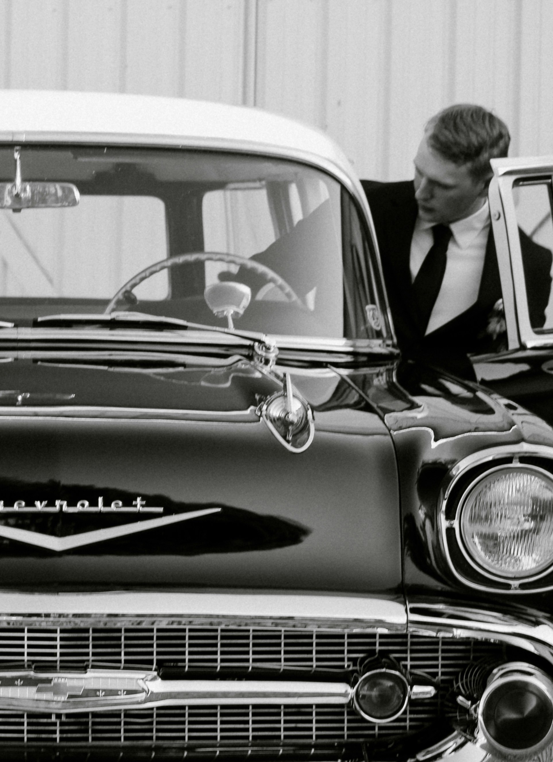 Clandestine Moment: a man in a suit steps toward a vintage Chevrolet