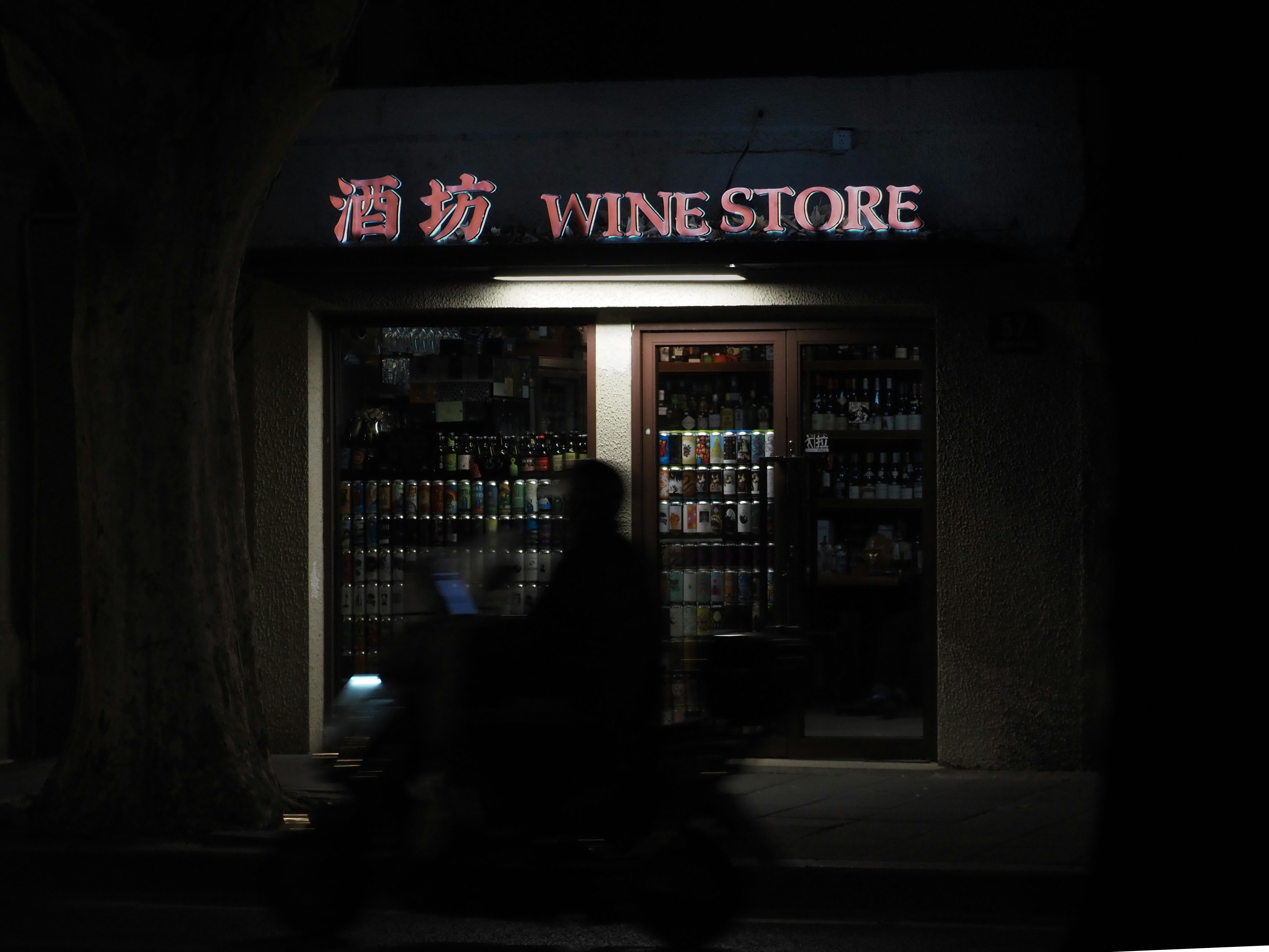 A wine store with bottles displayed at night.