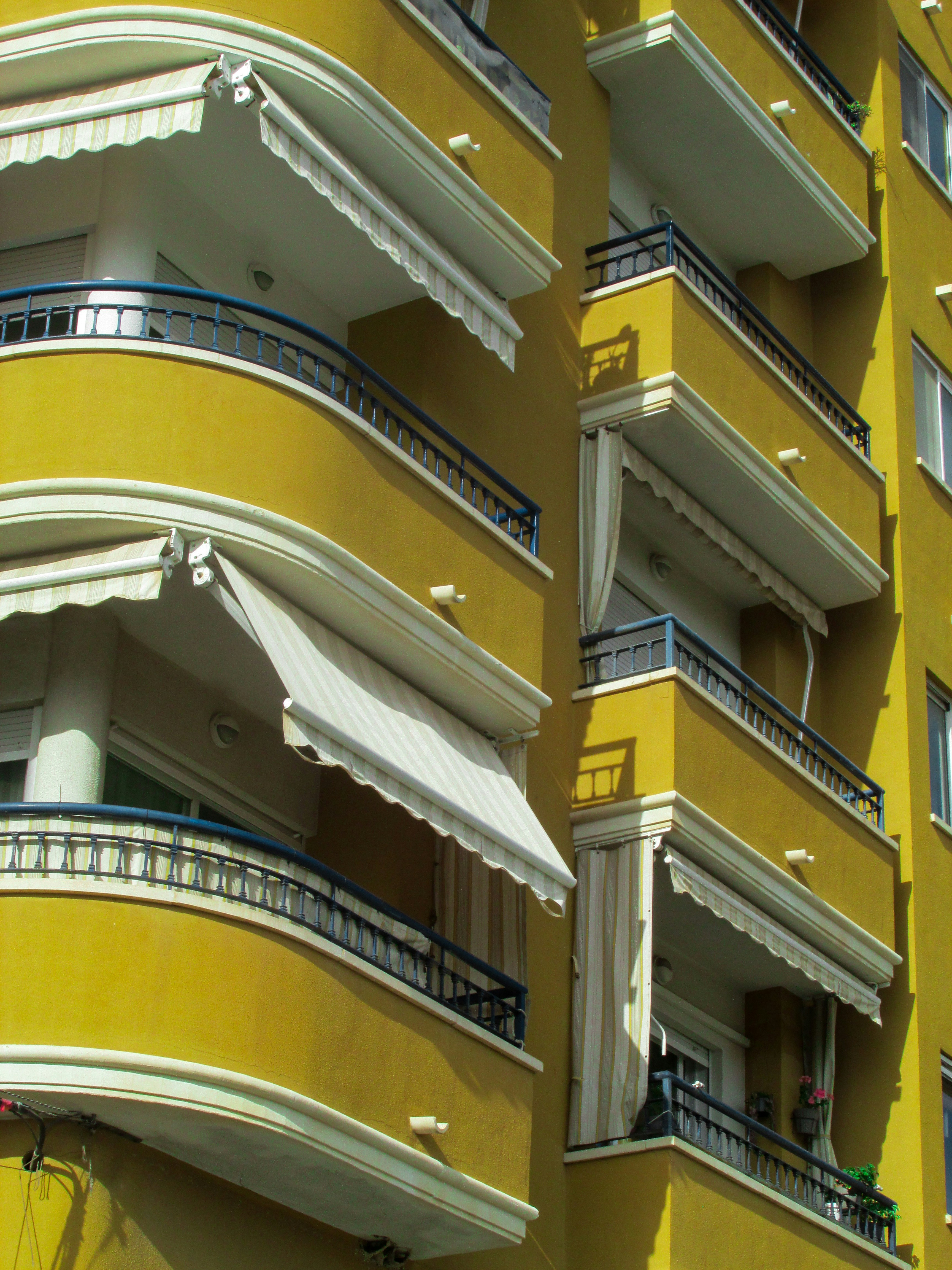 Yellow building with balconies and white awnings