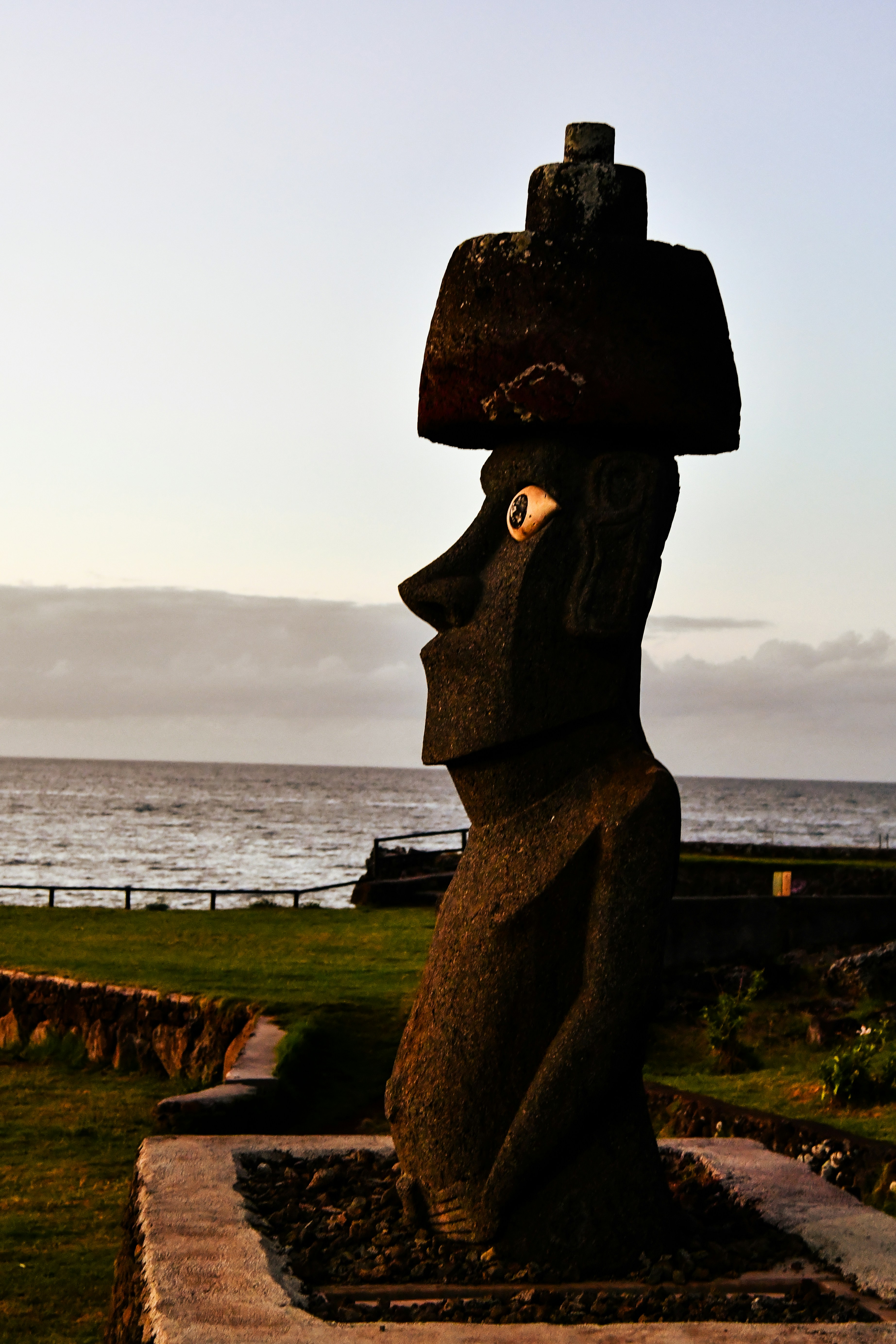 Stone Moai by the Sea: Sunset Silhouette on a Coastal Lawn