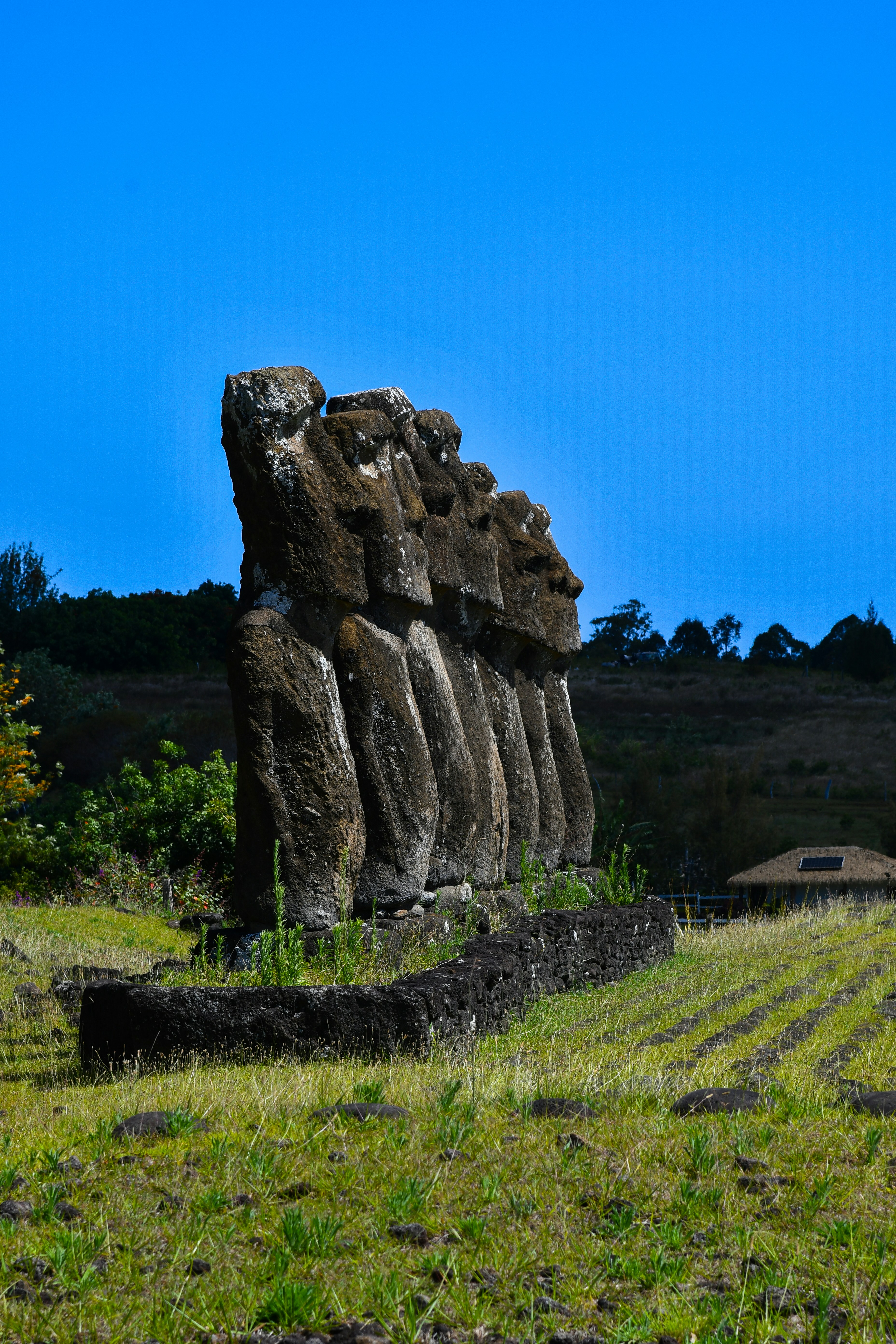 Monolithic Guardians: A Row of Ancient Statues Against a Clear Blue Sky