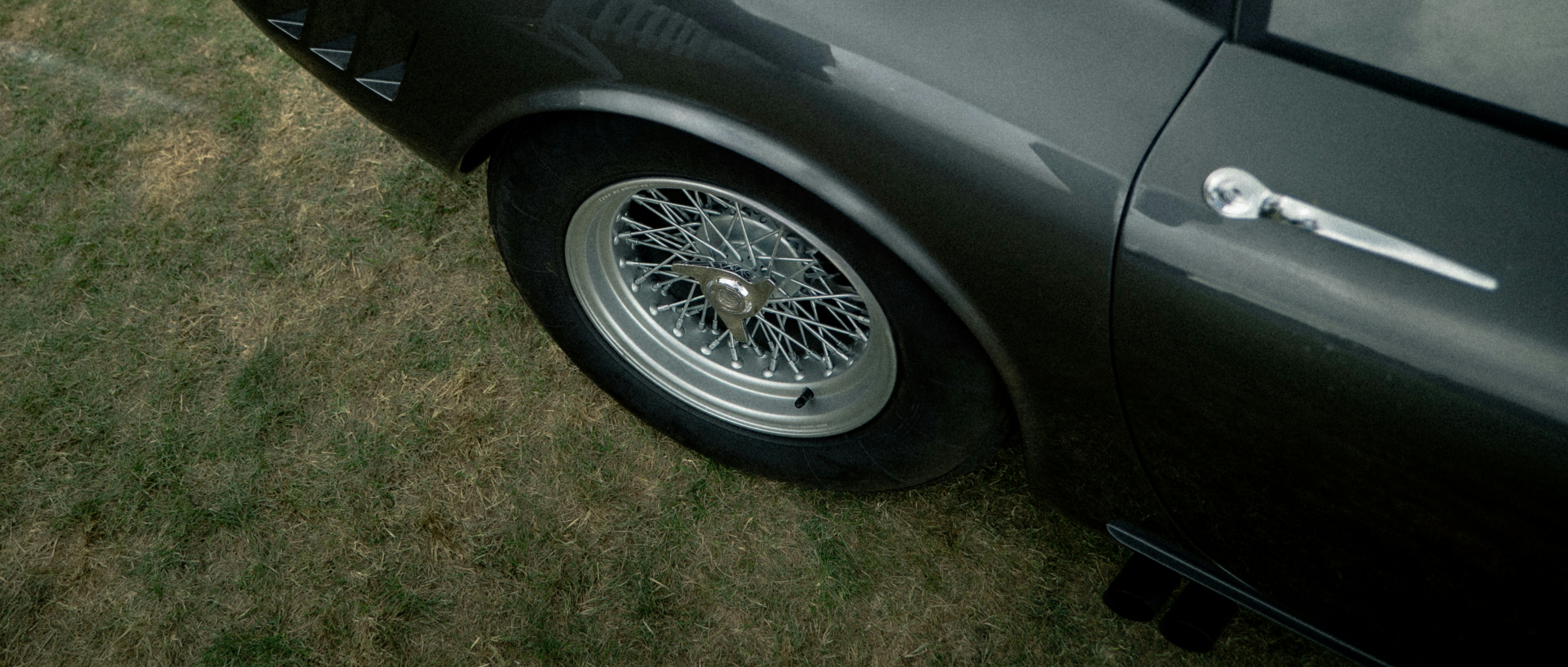 Close-up of a vintage car wheel and door handle.