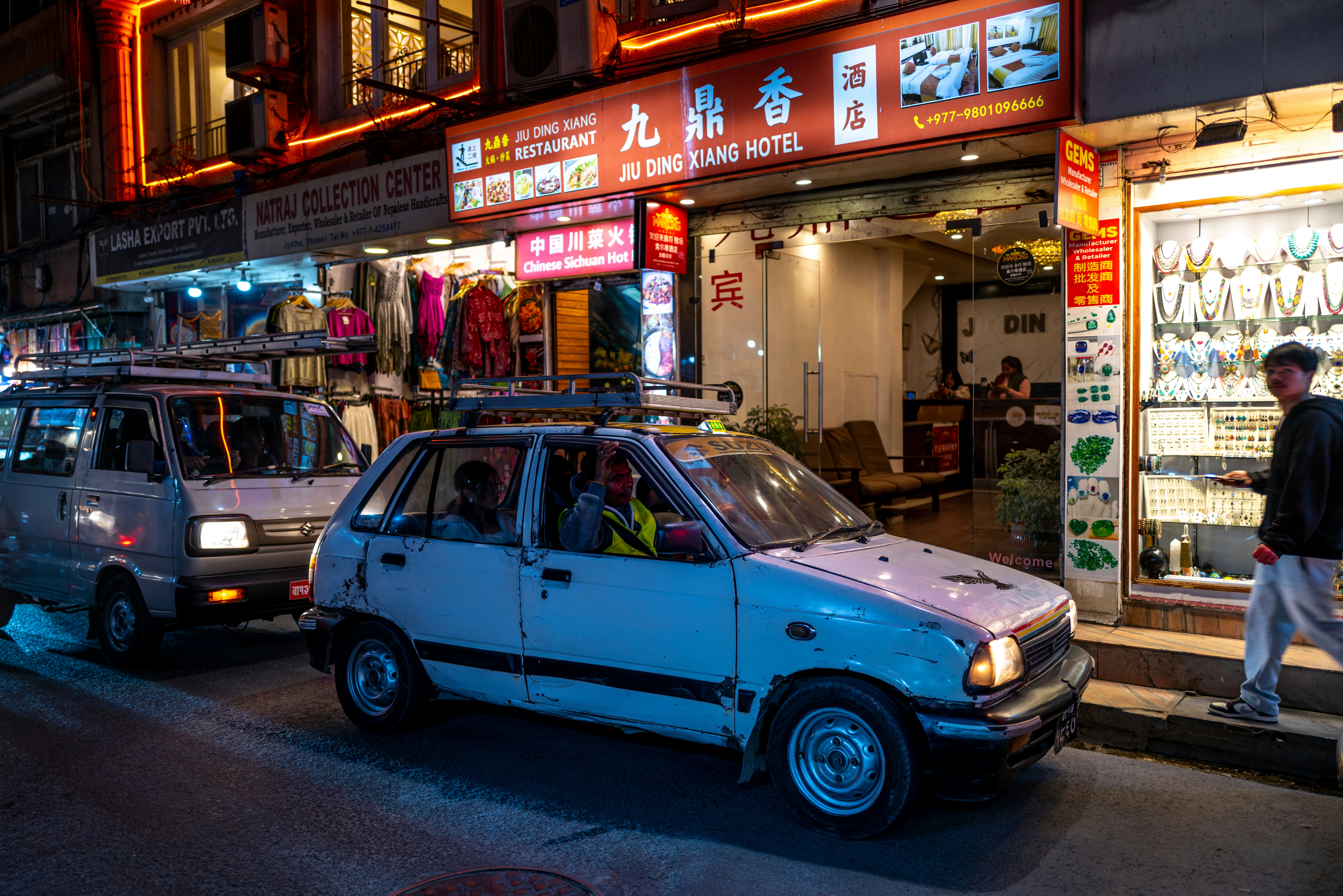 Blue Taxi Under Neon Signs in a Busy Night Street