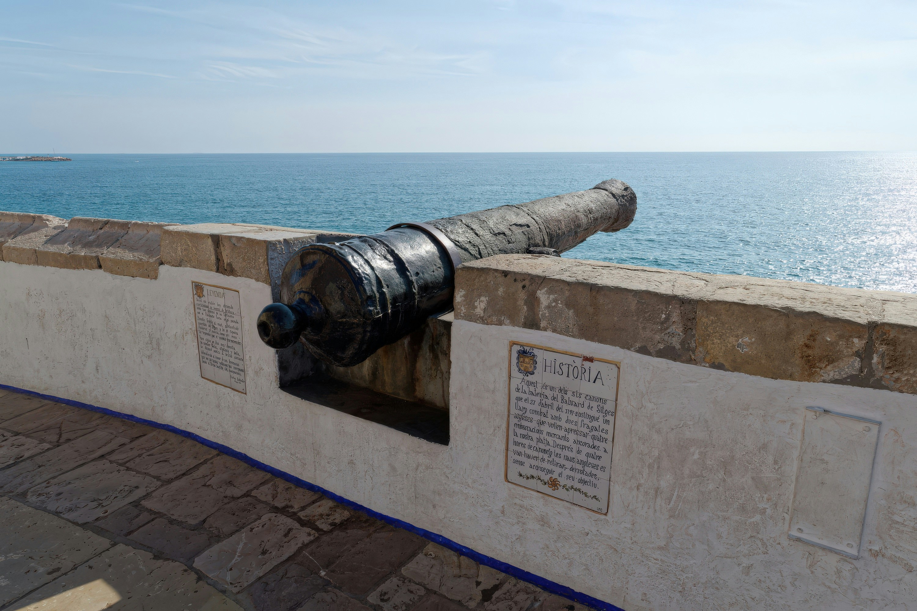 An old cannon on a stone wall overlooking the sea.