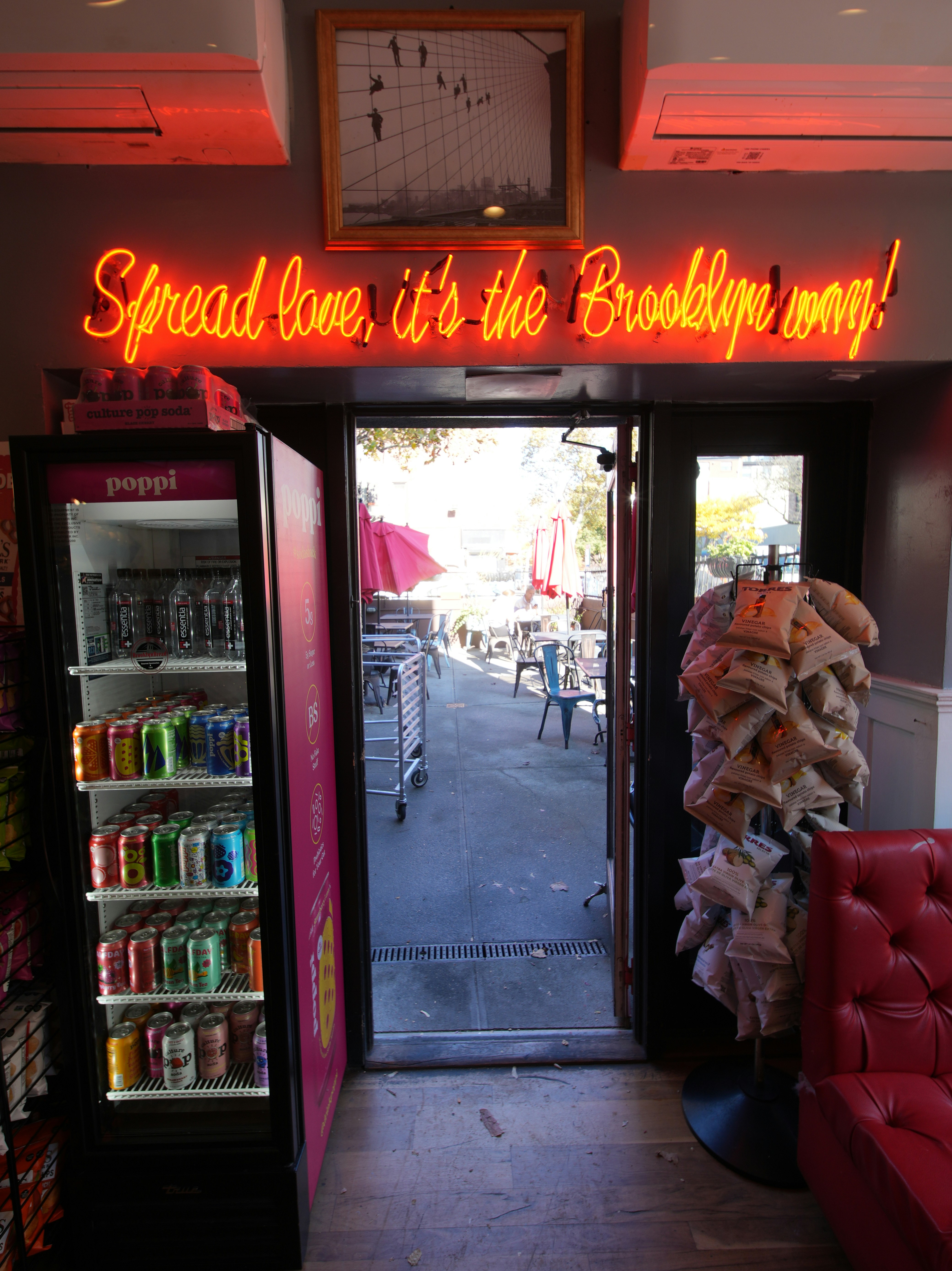 Neon Signover Entrance: A Cozy Café Threshold Framed by Red Lounge and Outdoor Patio