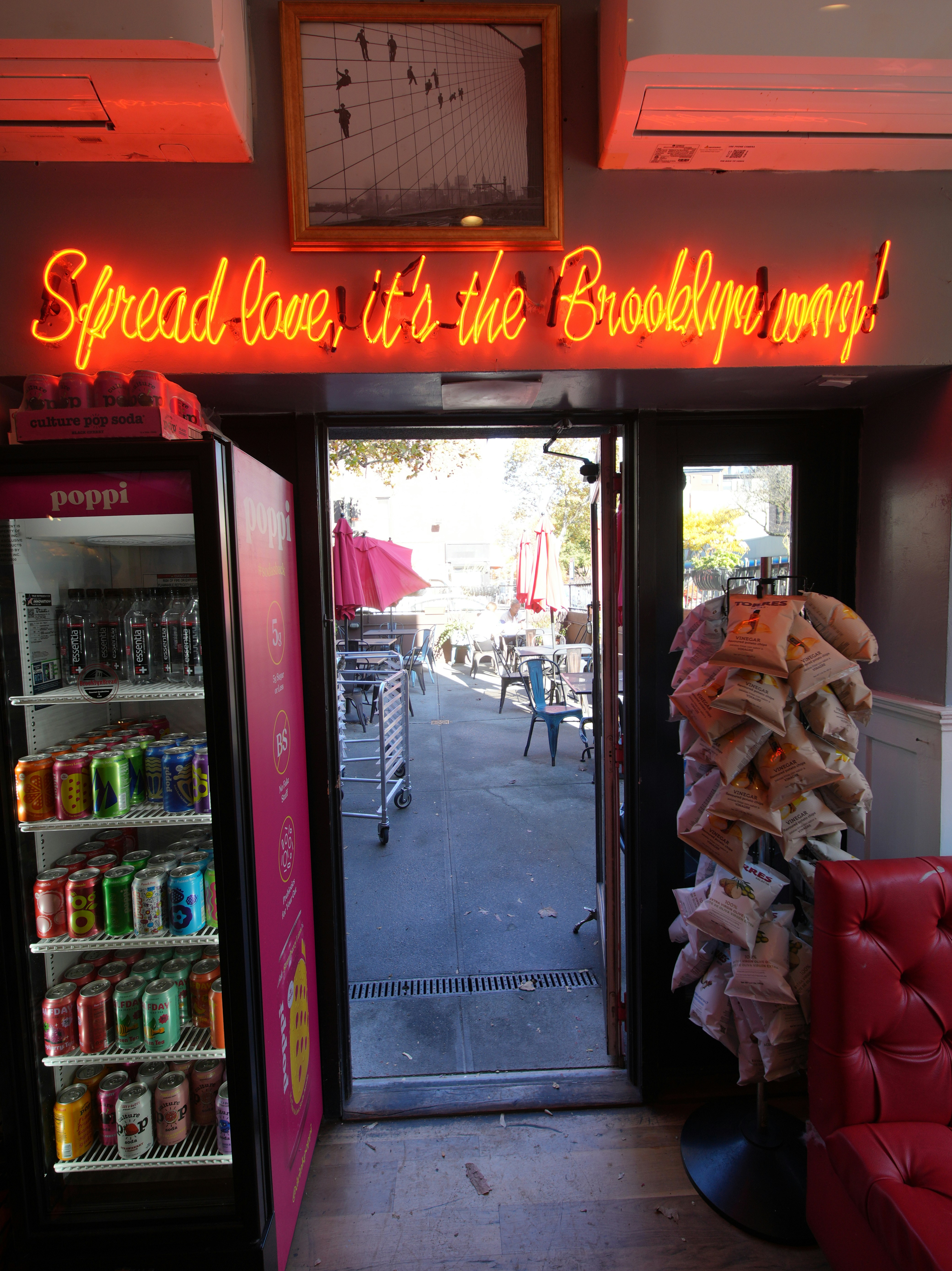 Neon Sign and Open Door to a Bustling Urban Café