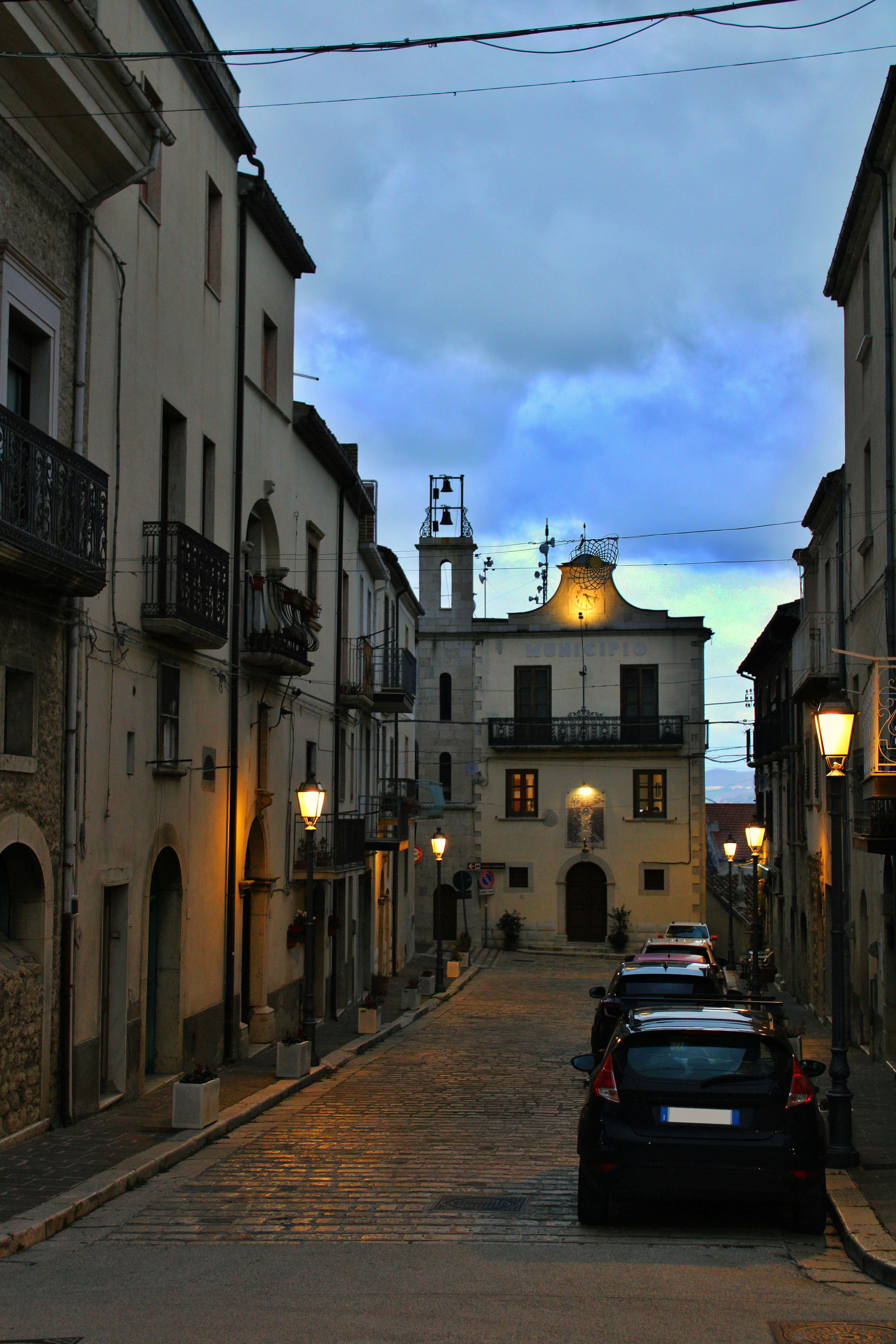 Evening Quiet: A Cobblestone Street Leads Toward an Illuminated Town Hall