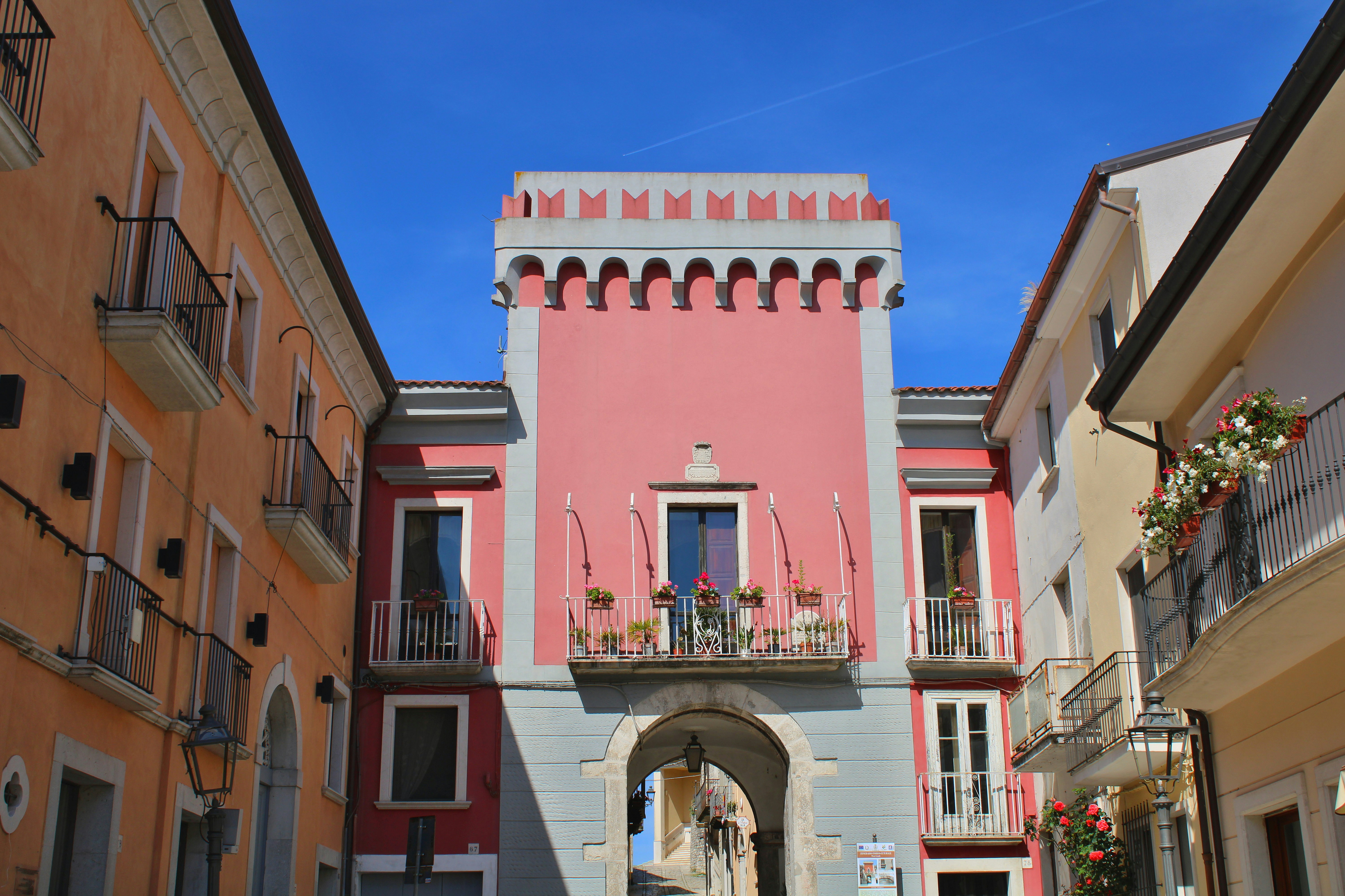 Archway in Coral Facade: A Bright Street Corridor Framing a Town Gate