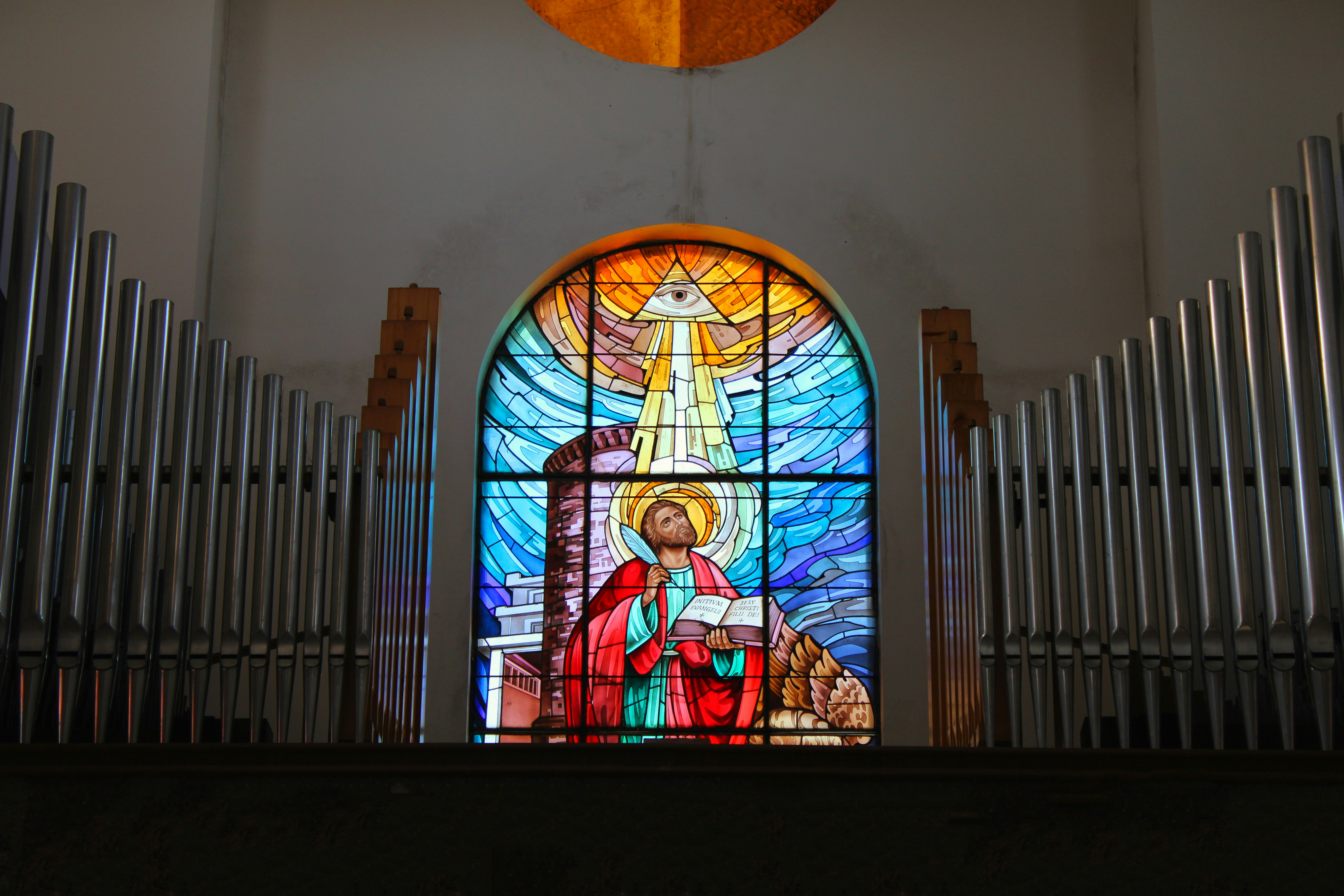 Glow from Sacred Glass: A Haloed Saint Amid Organ Pipes