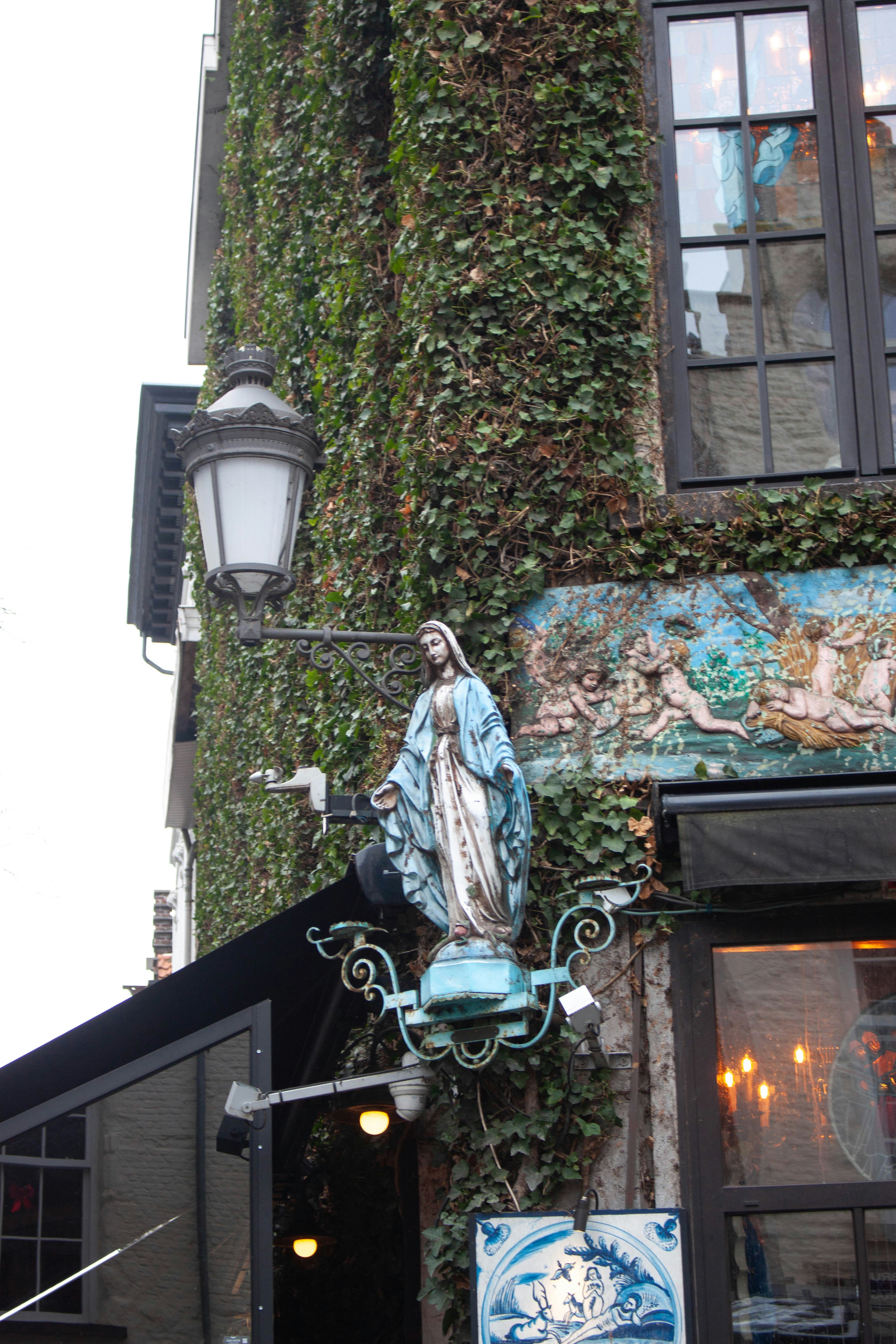 Statue of the Virgin under Ivy and Lanterns Adorns a Corner Café Facade