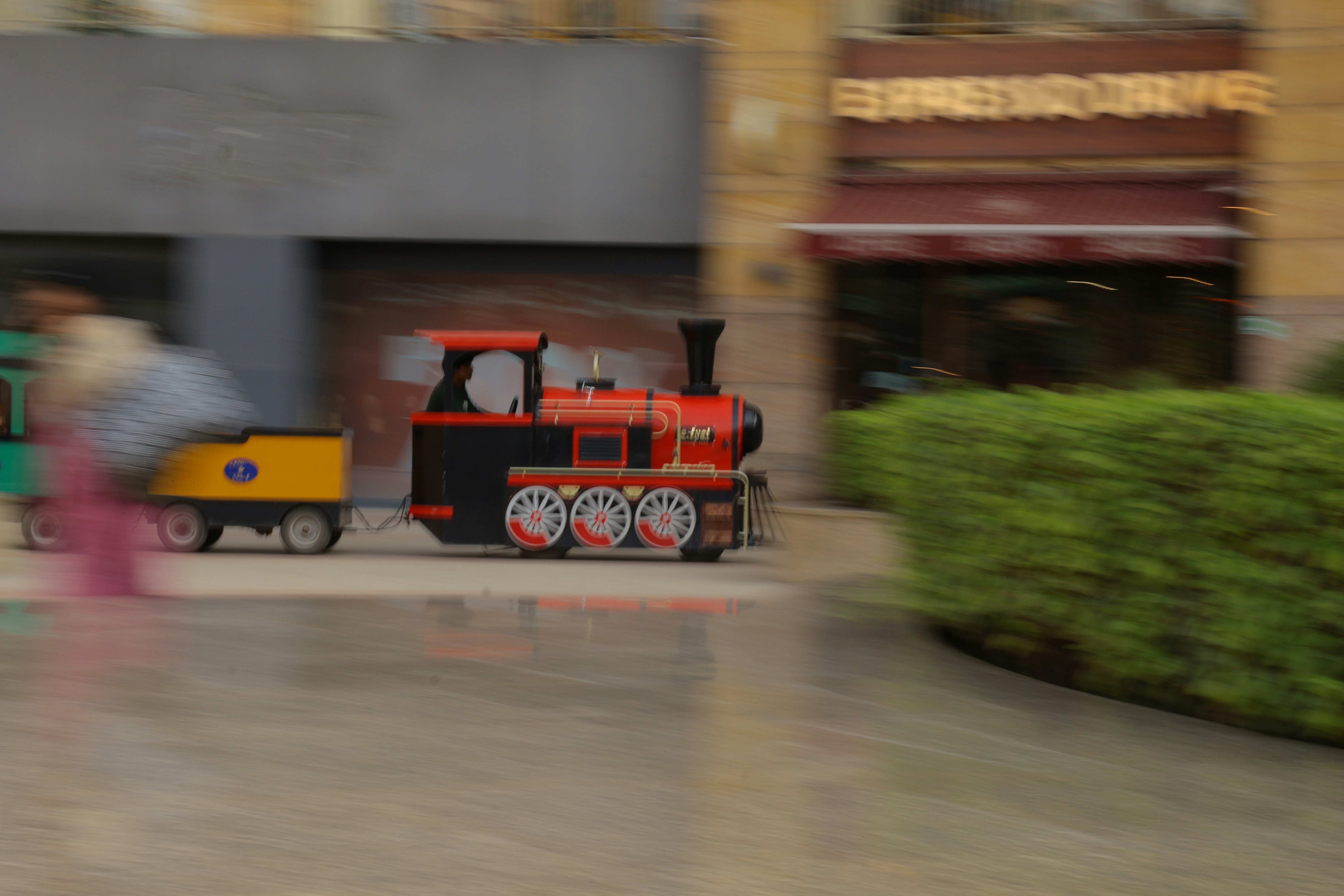 a colorful red toy train, motion blurred running on a mall floor