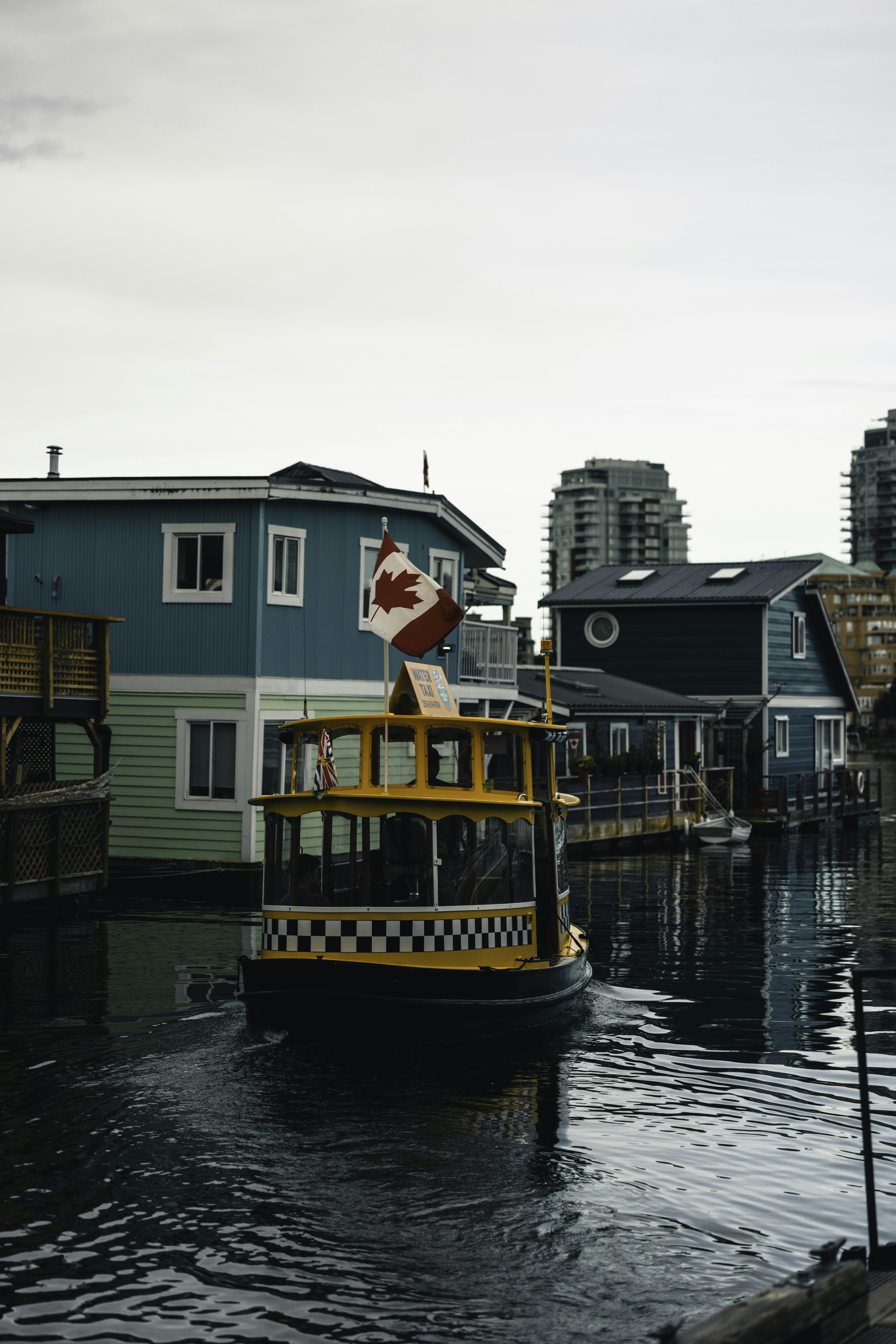 Yellow Boat Crossing: A Canadian Flag Glides Past Bright Waterfront Homes