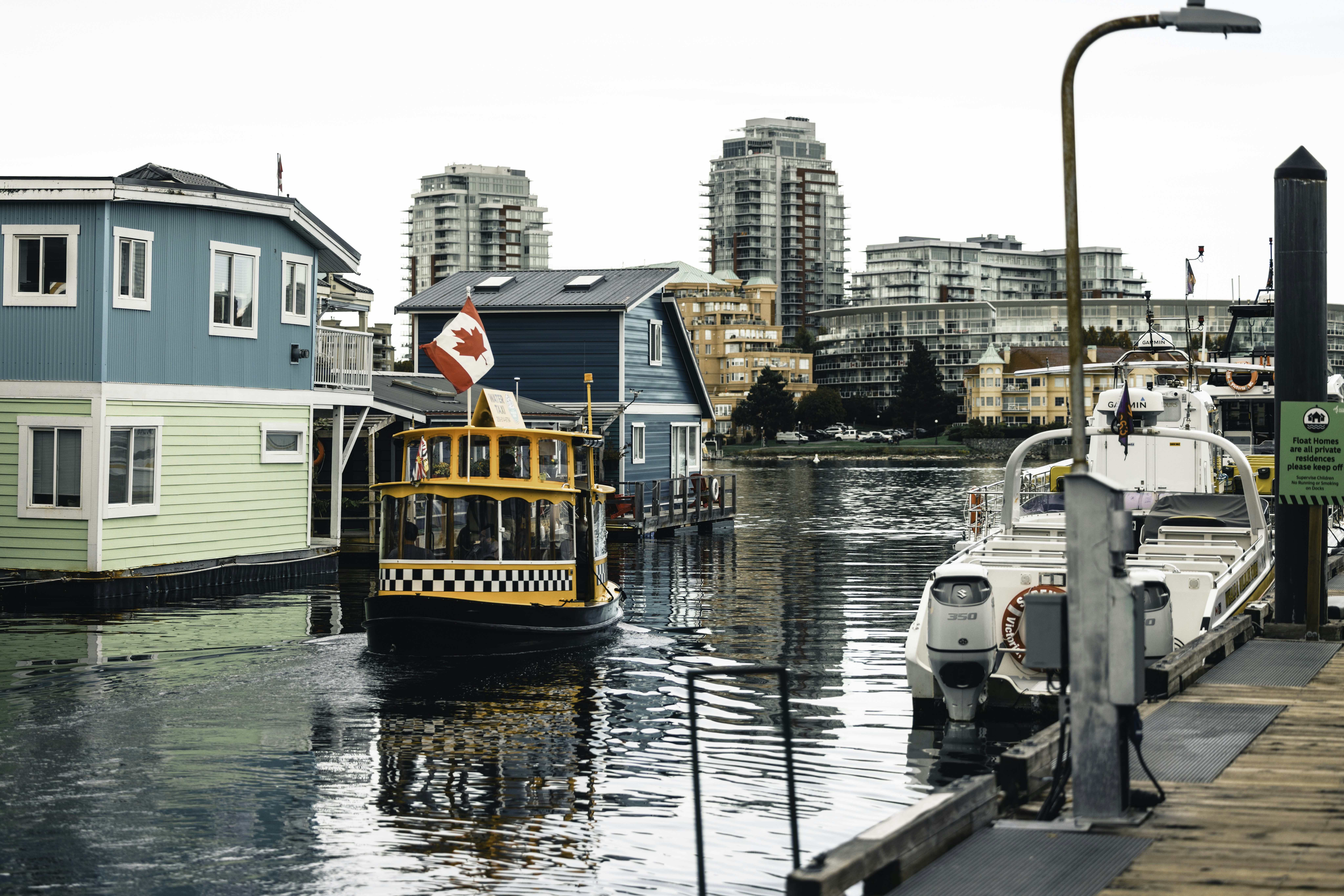 Floating Corridor: A Vancouver-like Channel with Colorful Houseboats and a Sturdy Yellow Vessel