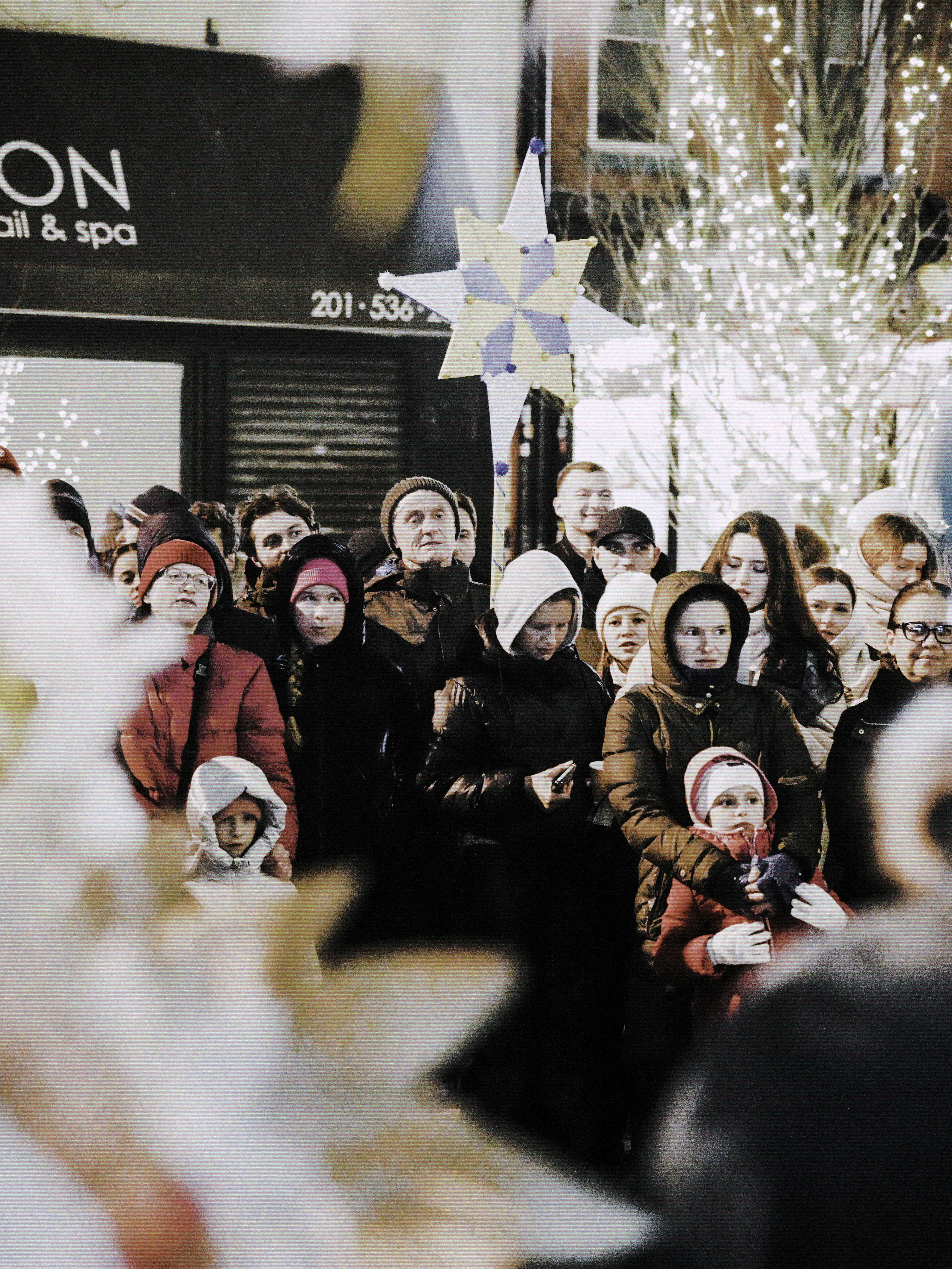 Crowd Gathers Under Starry Holiday Lights as a Star Ornament Pays a Visit