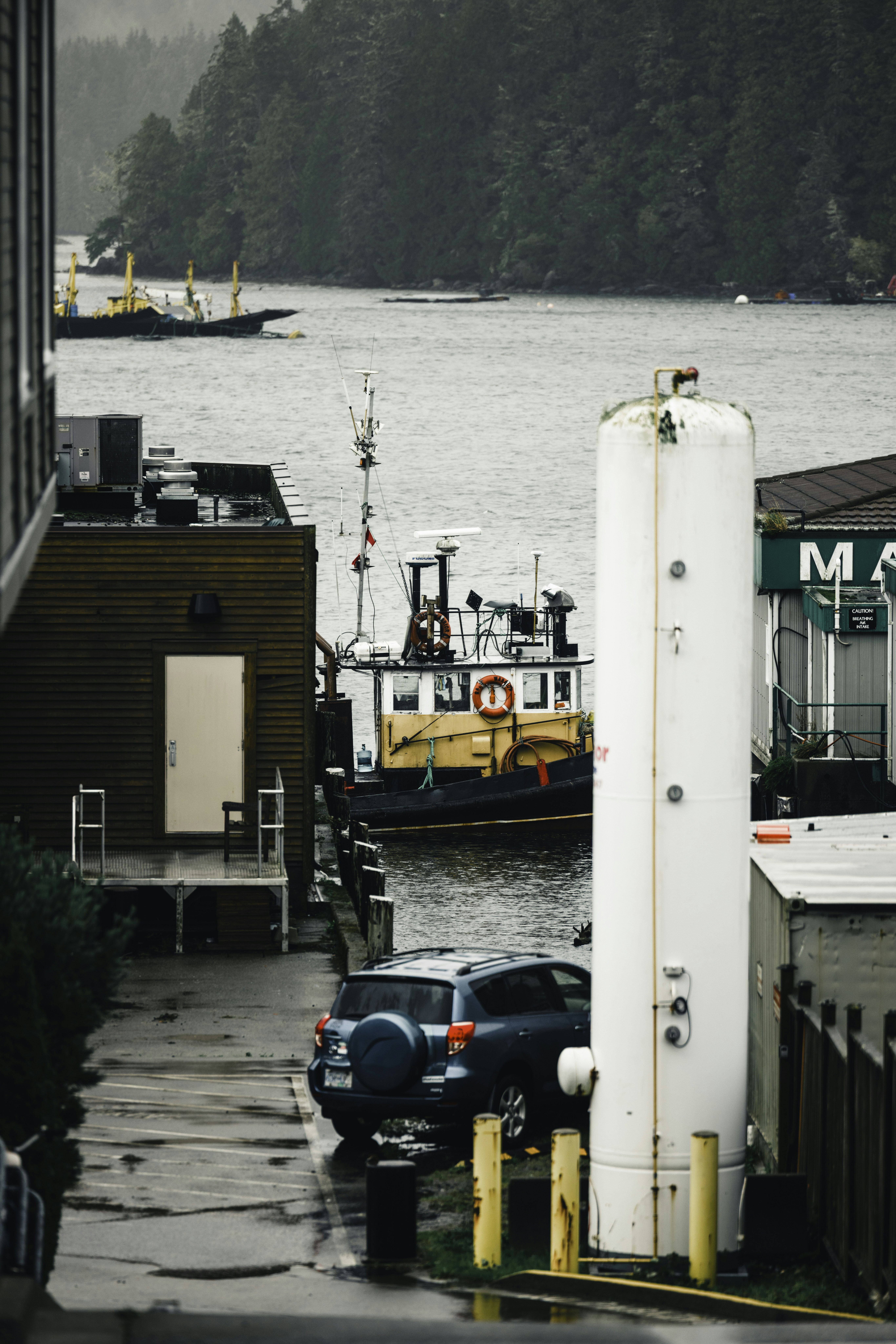 Barco atracado perto de prédios industriais e um carro. foto – Imagem ...