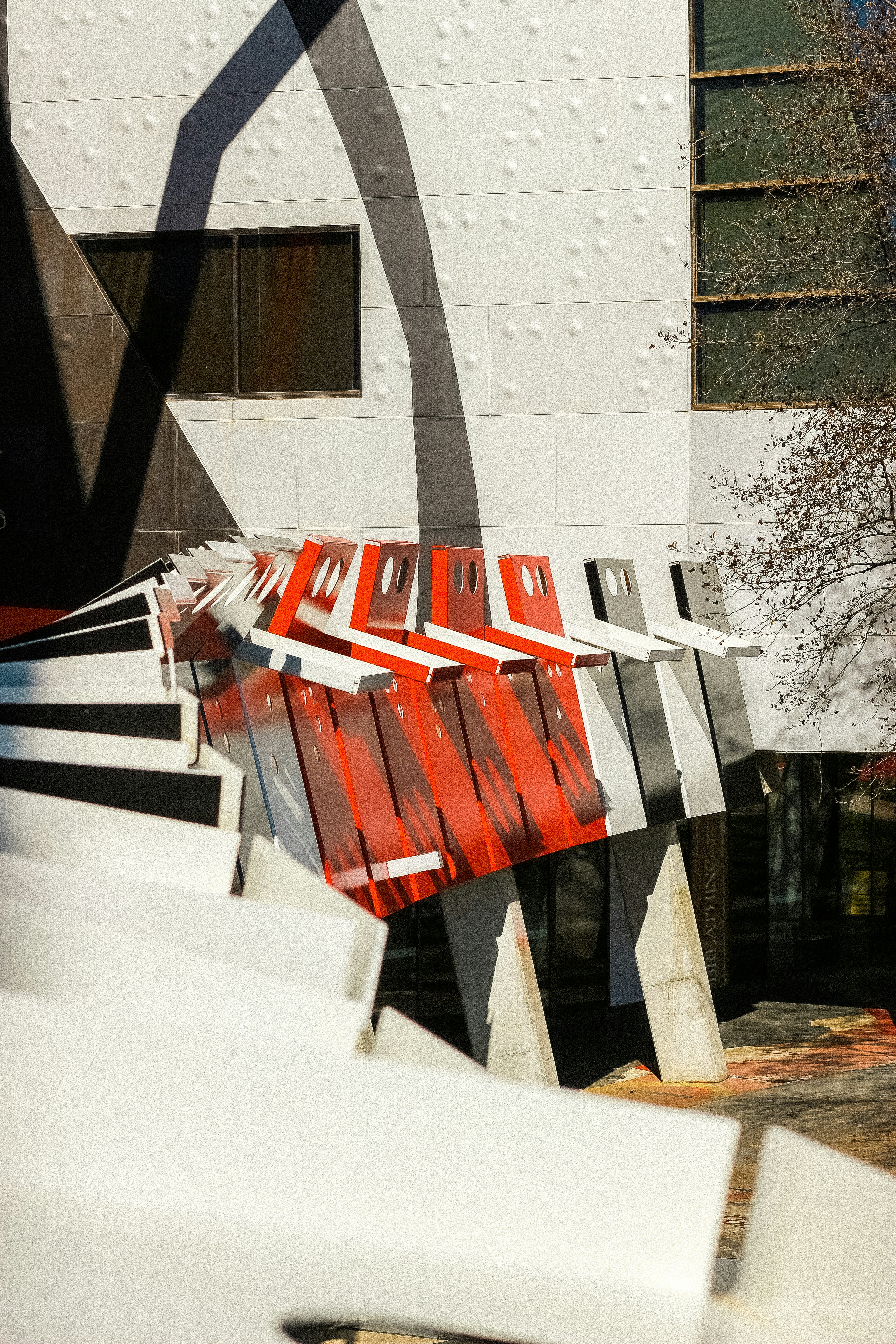 Red-and-white angled sculpture corridor under architectural arch