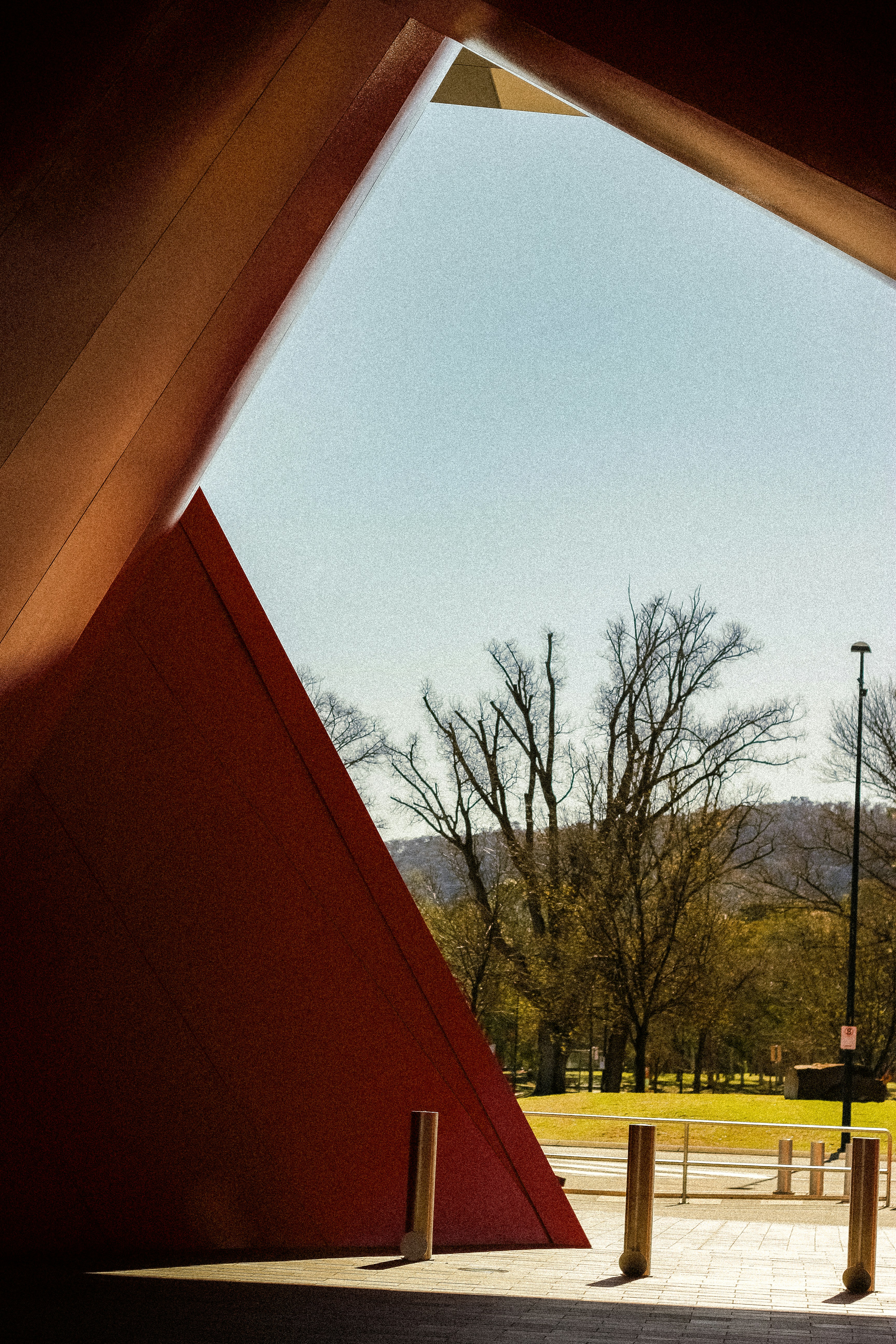 Architectural Triangle: Red Facade Framing a Quiet Park