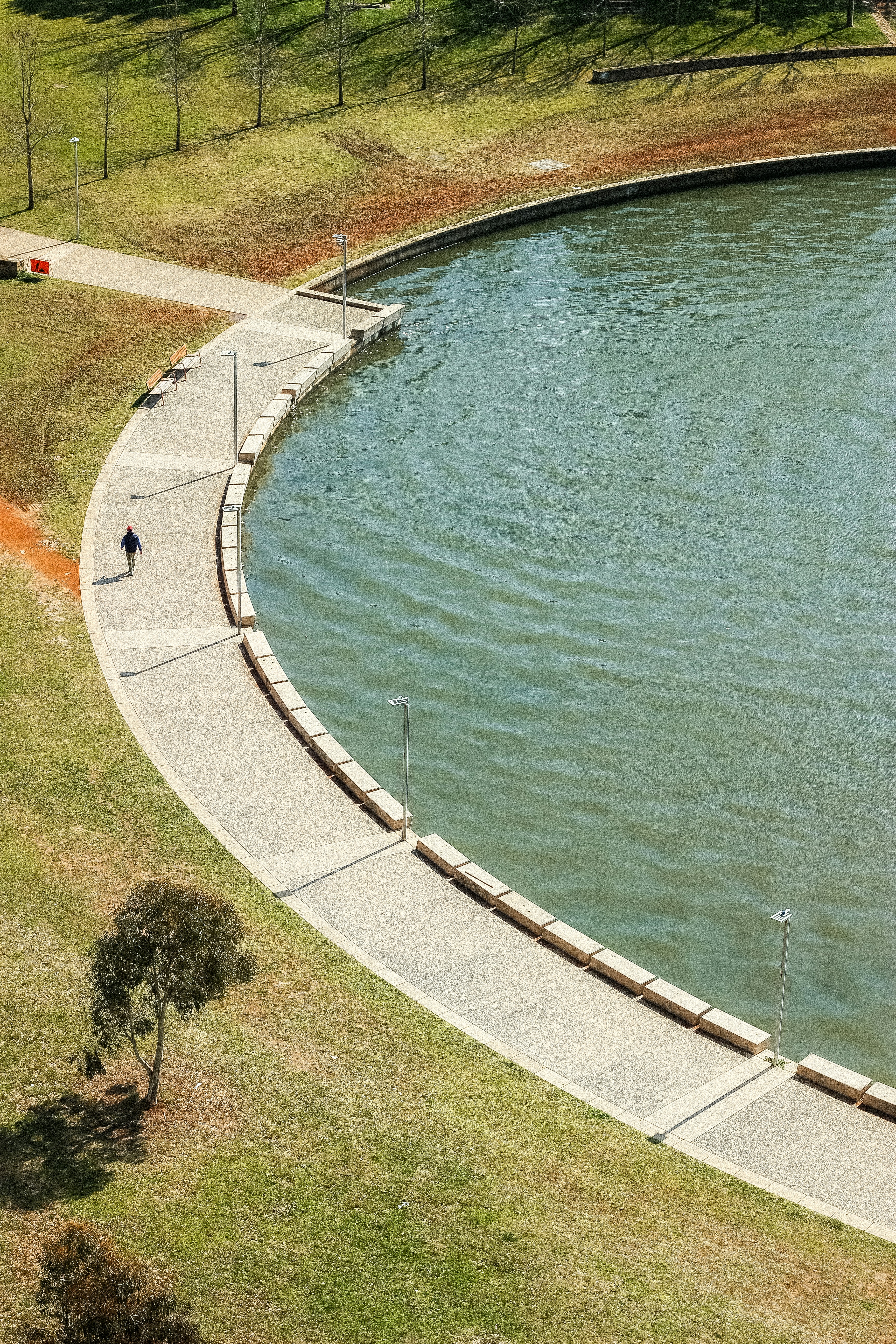 A quiet arc: lone figure strolling along the curved riverside promenade